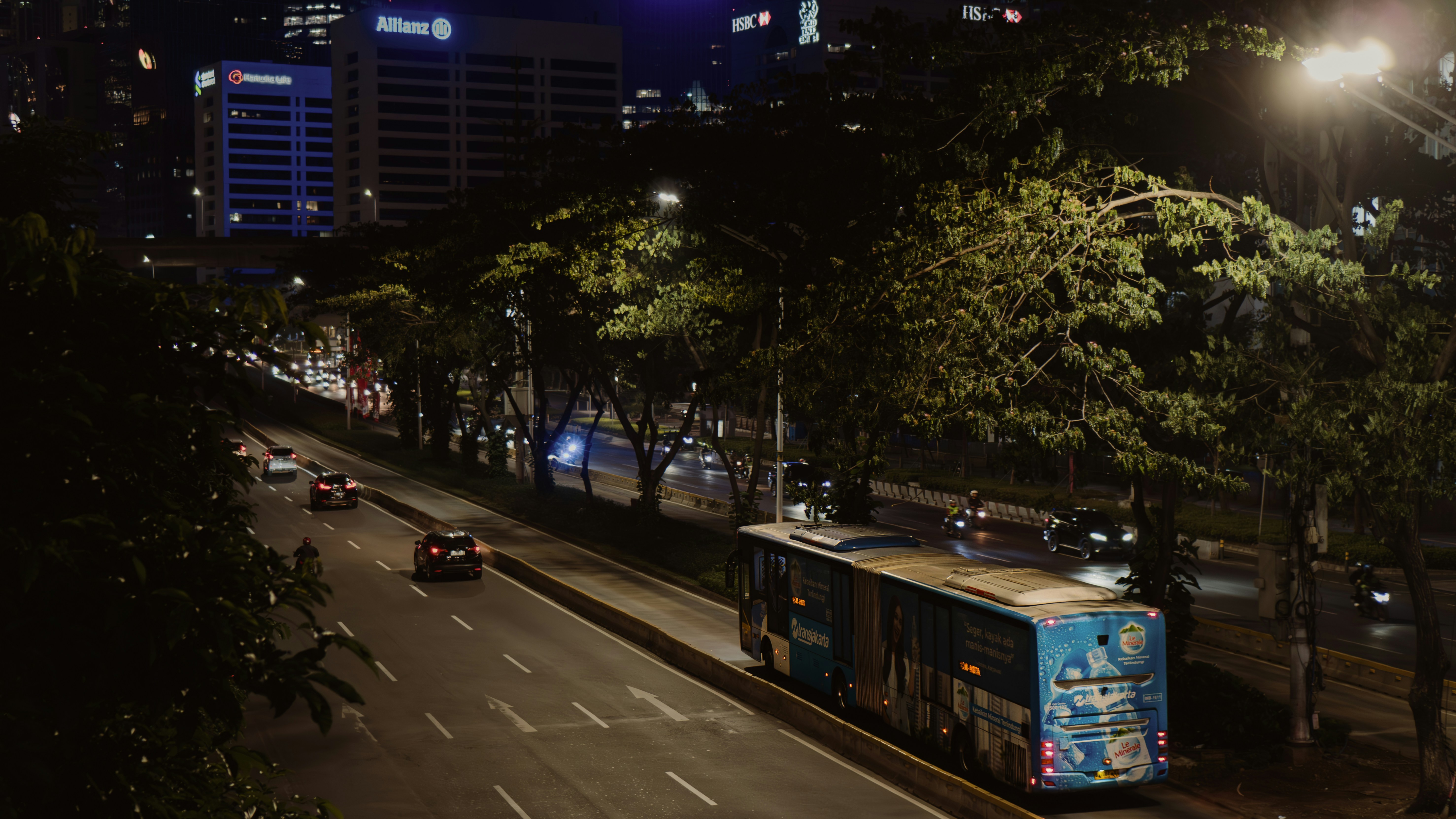 Blue Bus on a Nighttime Boulevard: Neon Reflections and Quiet City Motion