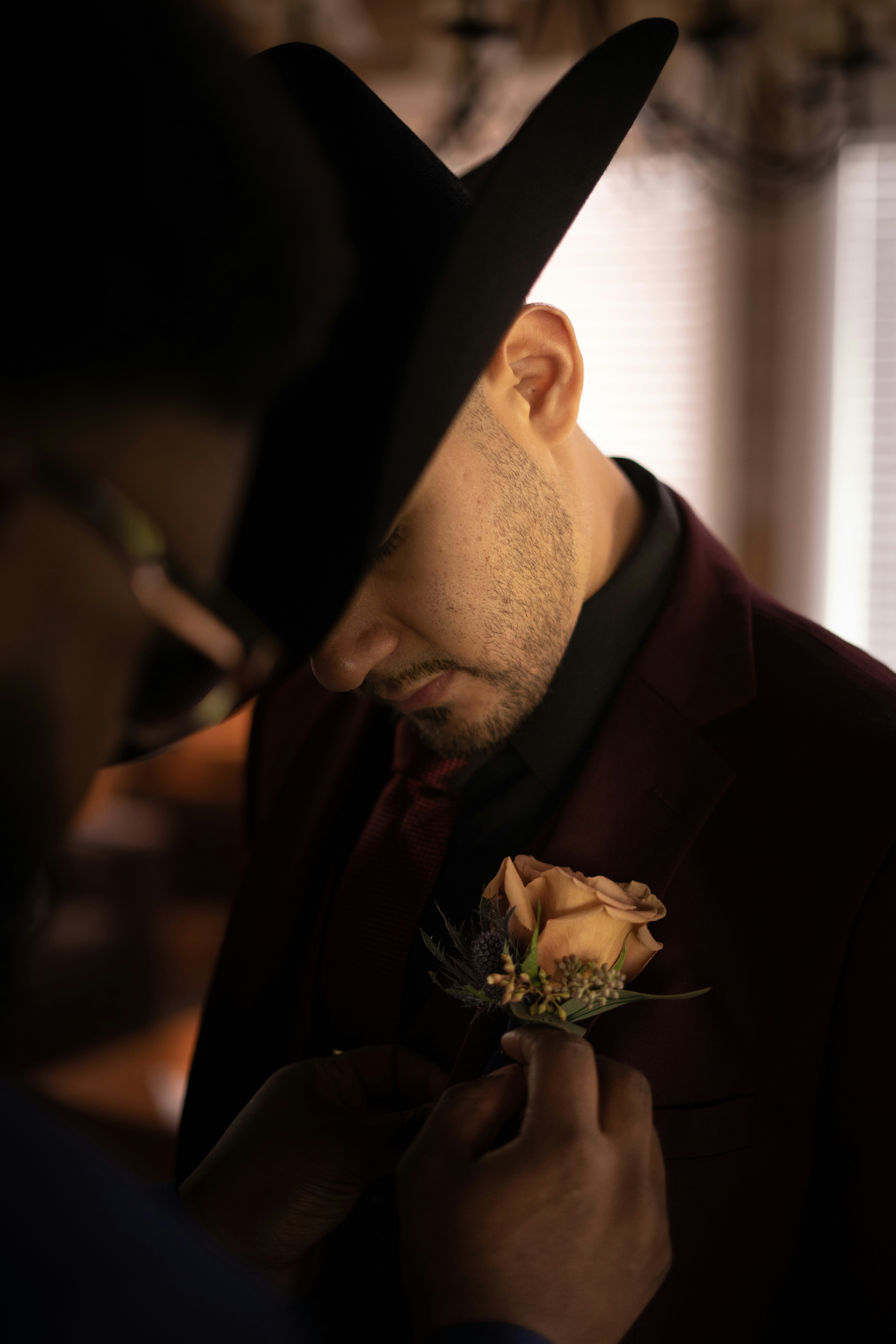Warm Indoor Moment: Pinning a Peach Rose on a Burgundy Suit