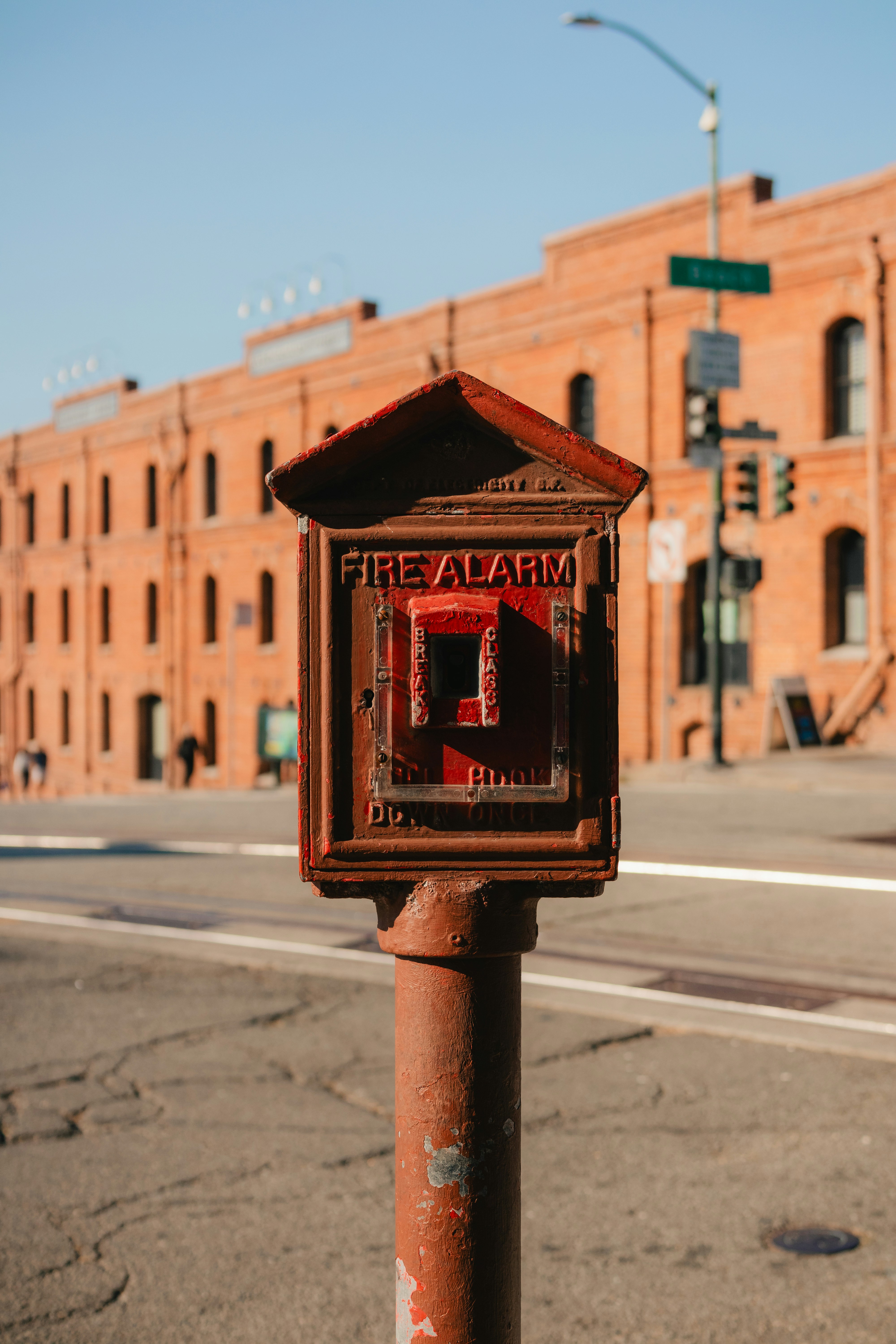 Rusted Fire Alarm Box in a Sunlit Brick Street