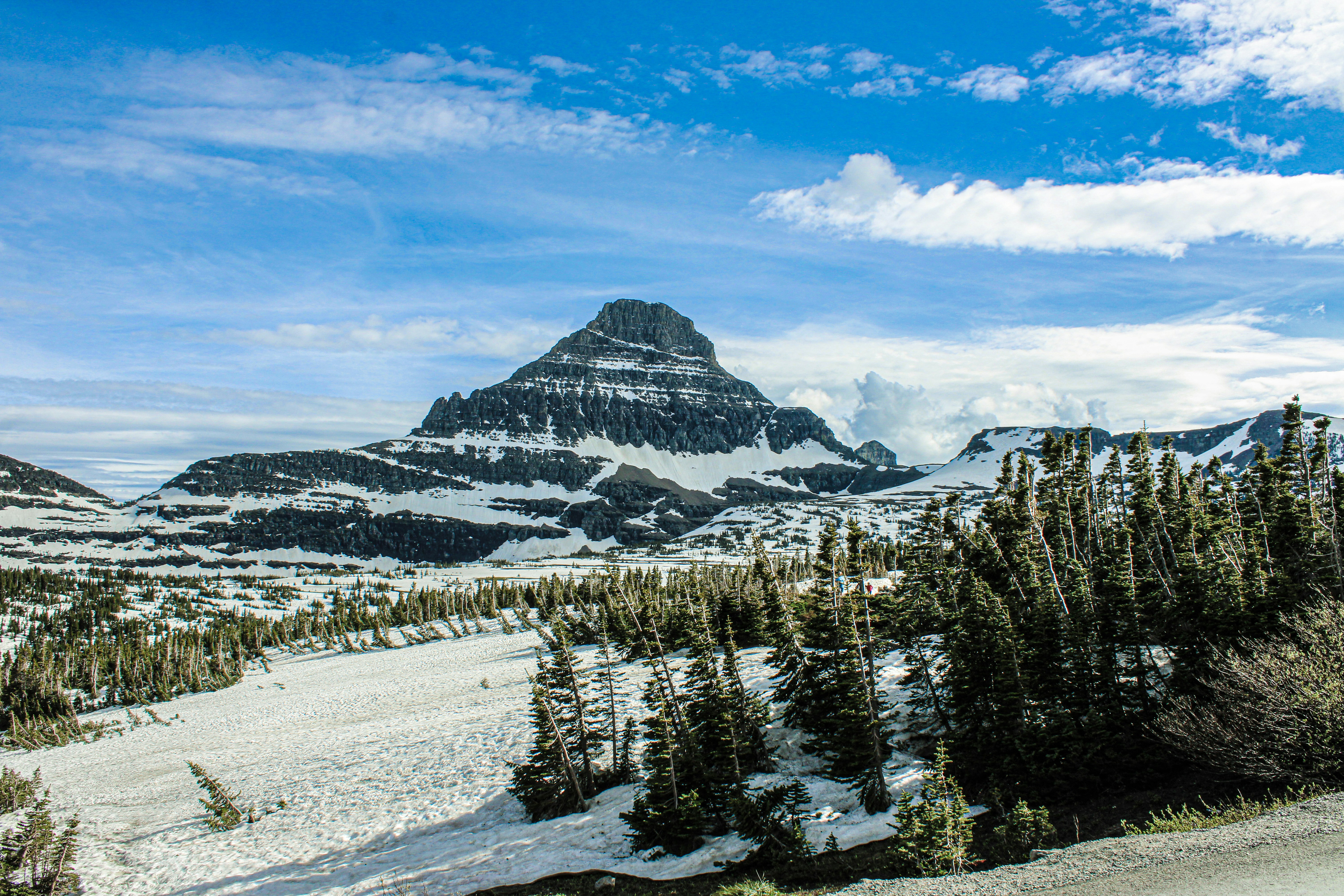 Snow-dusted mountain under a bright blue sky with scattered clouds.