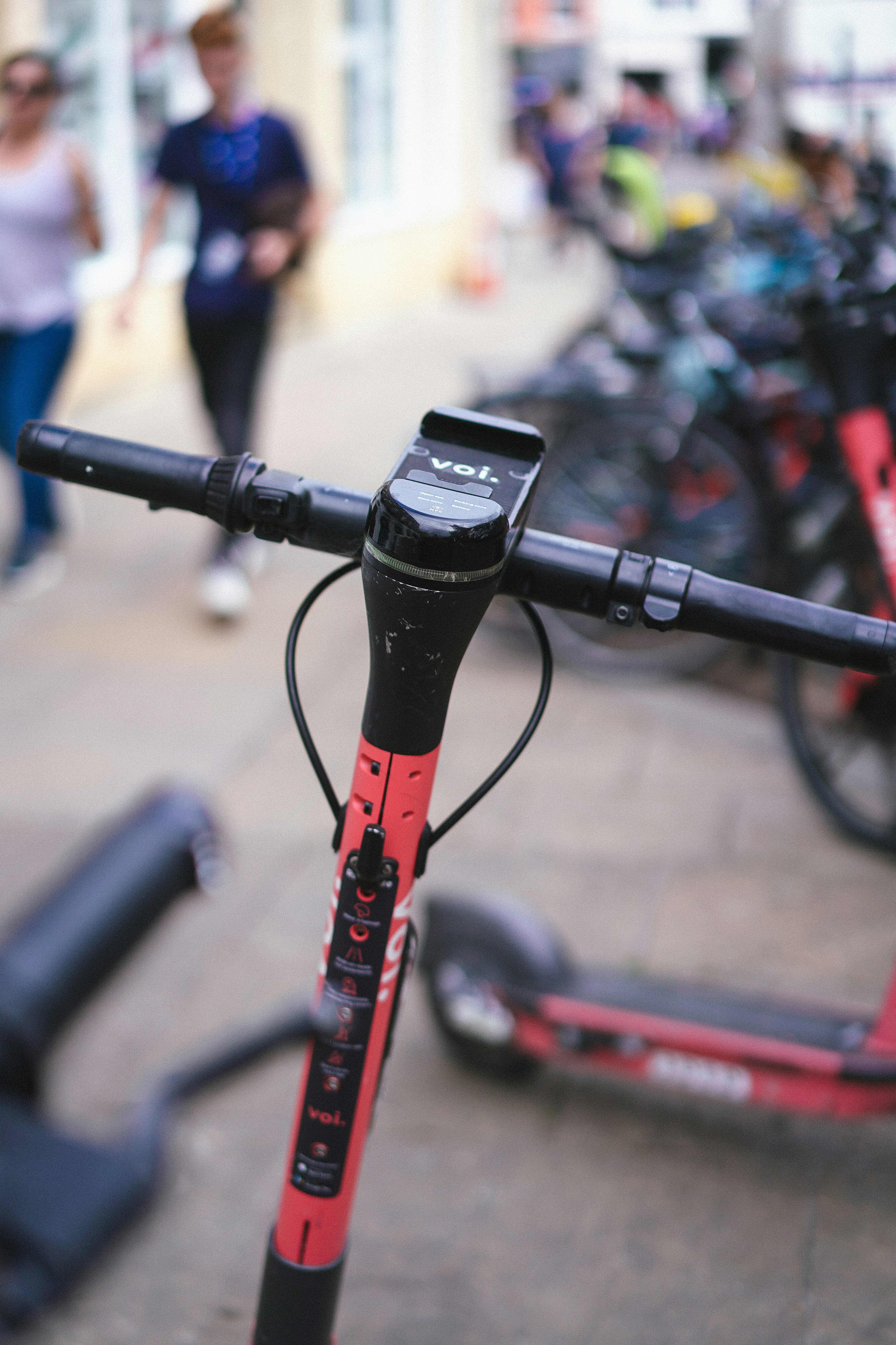 Locked in the Ride: A Close View of a Red-Tone Scooter Mast on a Busy Street