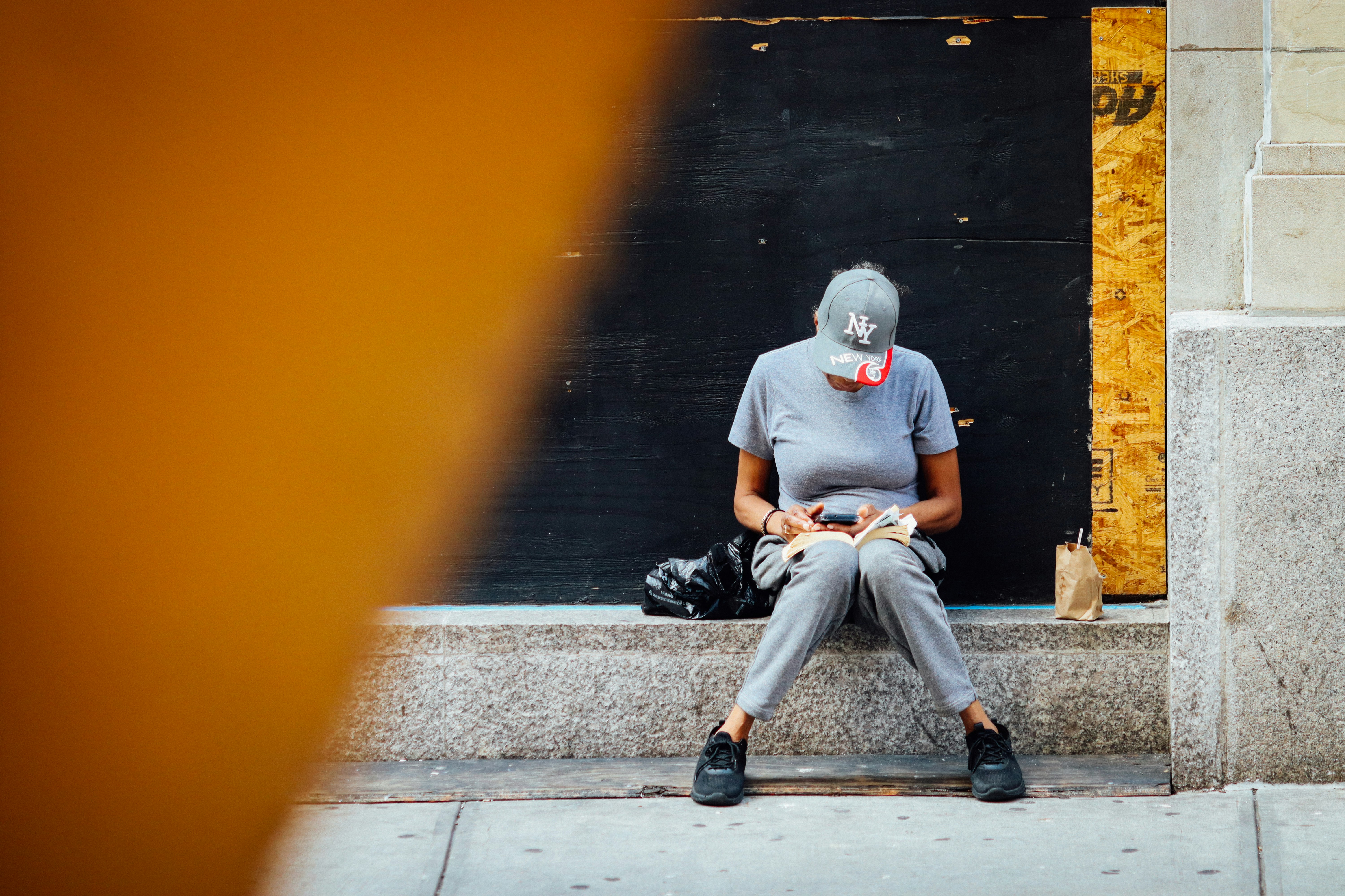 City Steps, Quiet Focus: A Reader Framed by Orange Blur