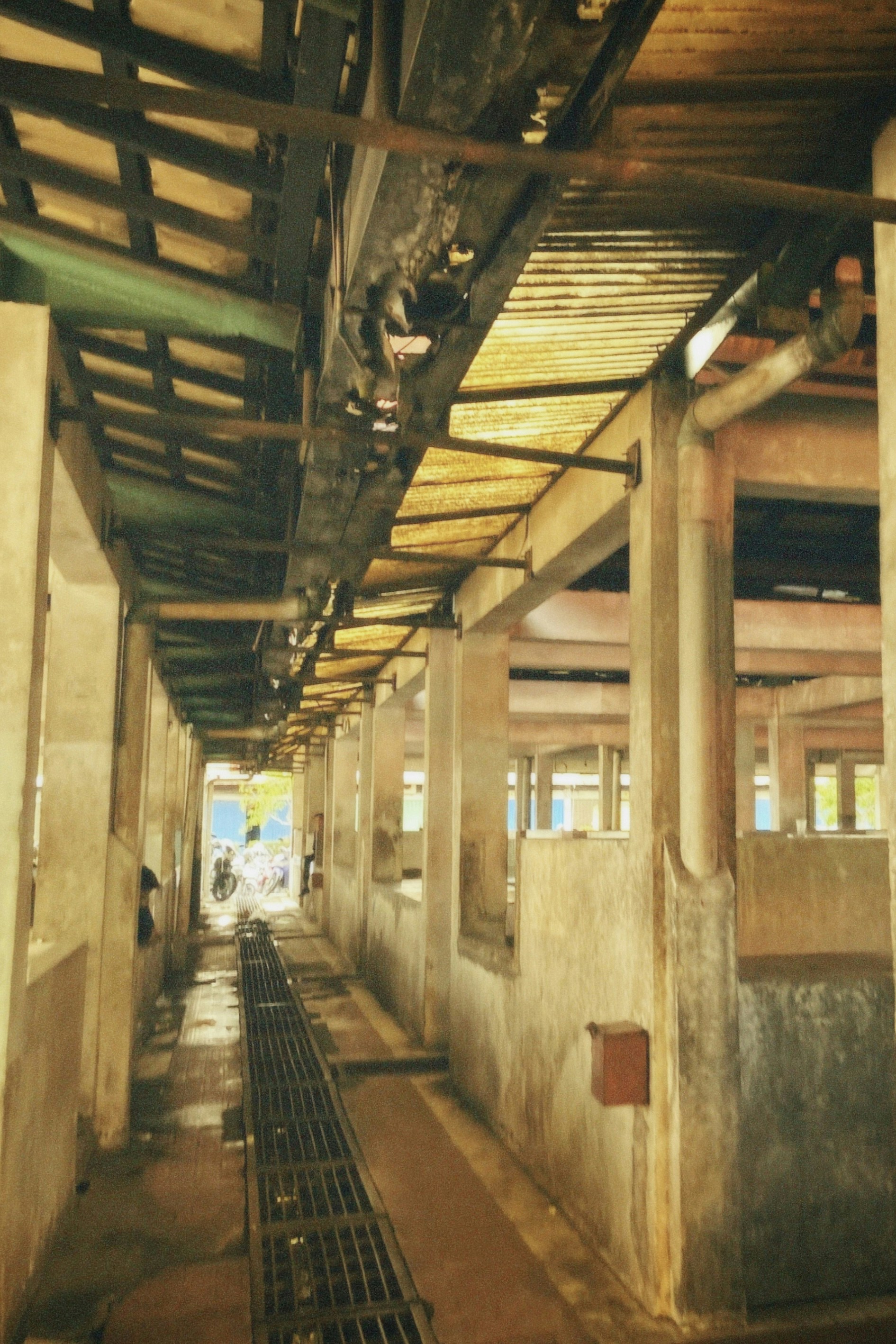 Long Corridor of Warm Light: An Industrial Passage Framed by Pipes and Concrete