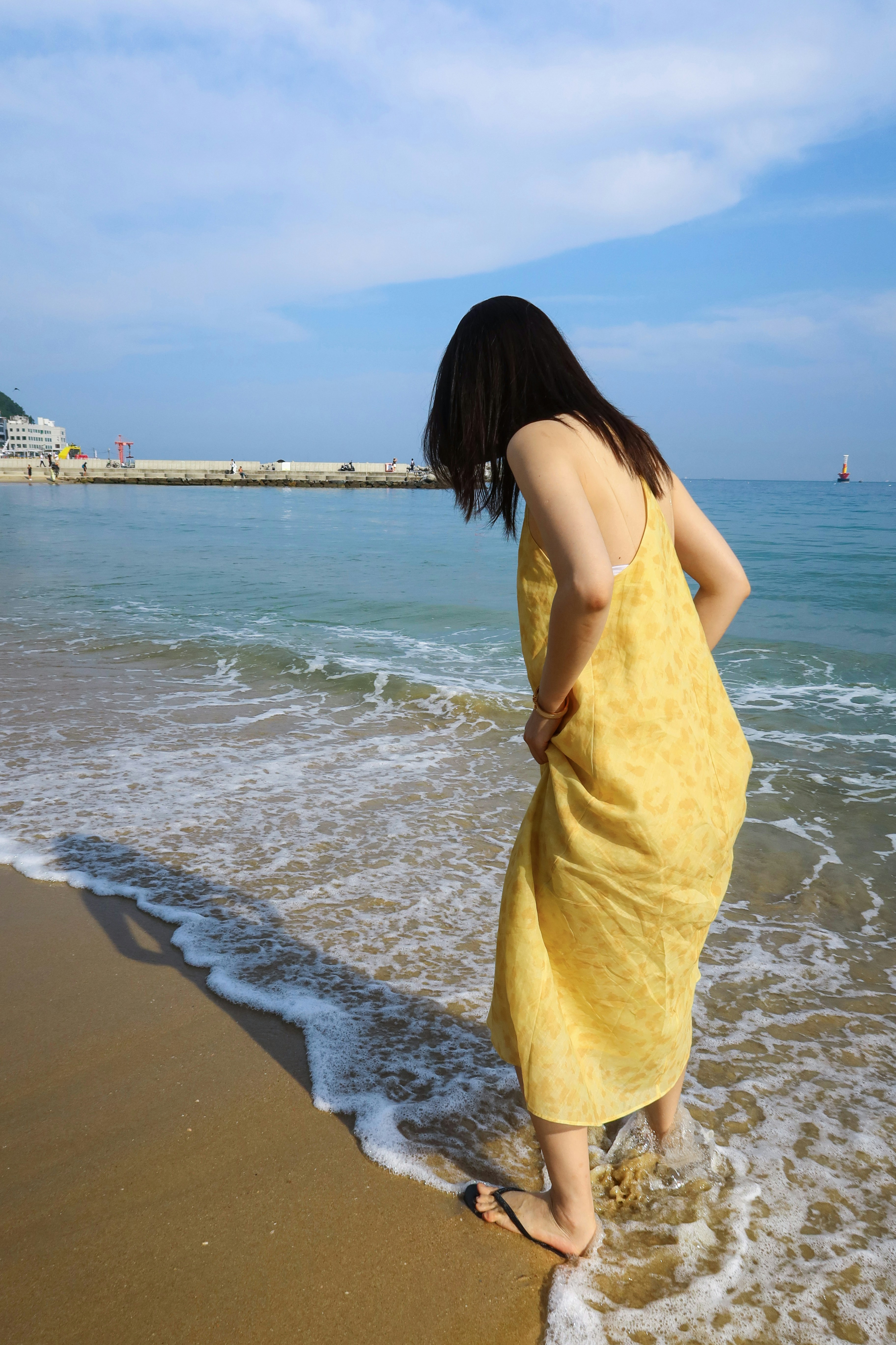 A woman in a yellow towel walking into the ocean photo – Free Beach ...
