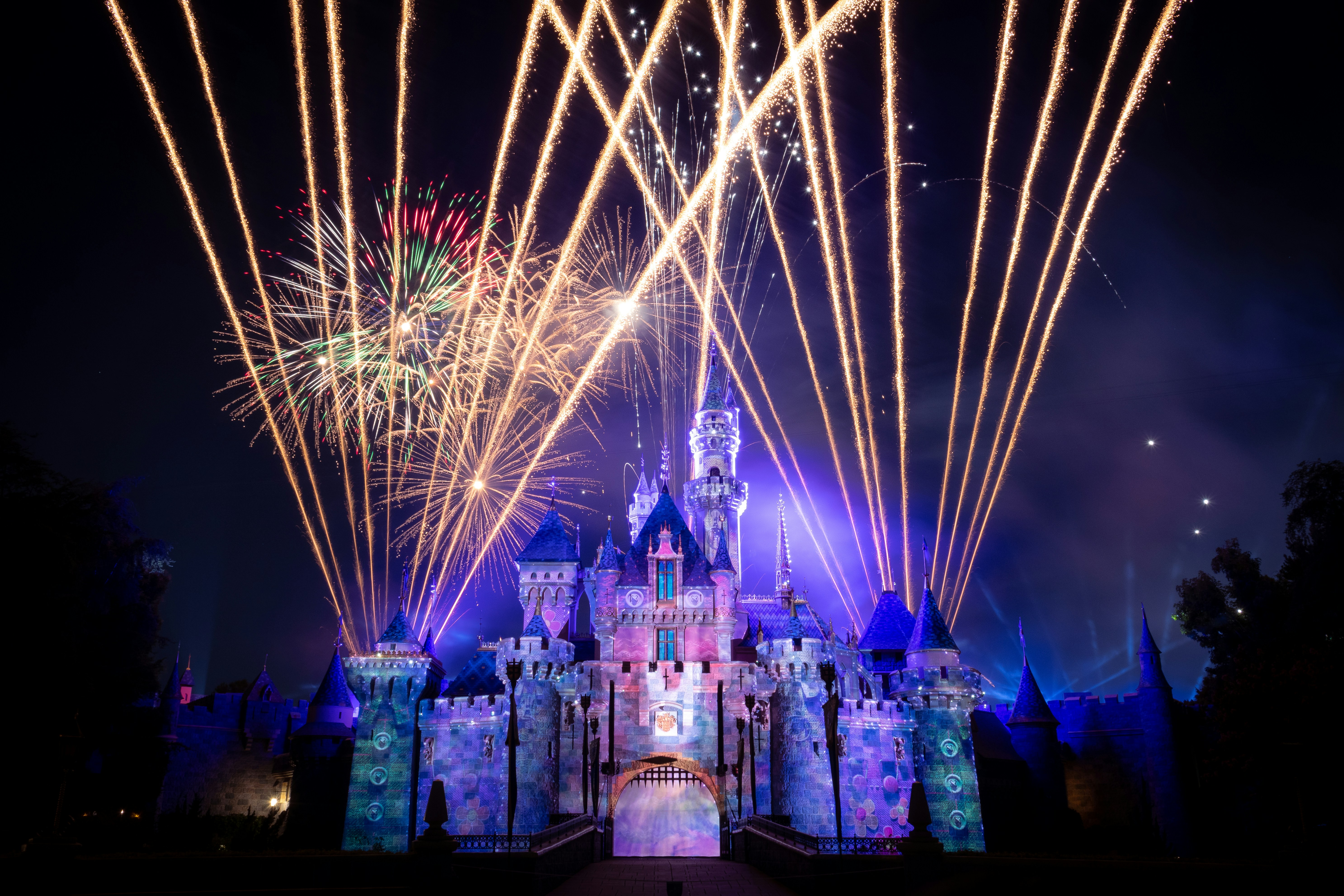 Fireworks illuminate a castle at night with vibrant colors and intricate lighting.