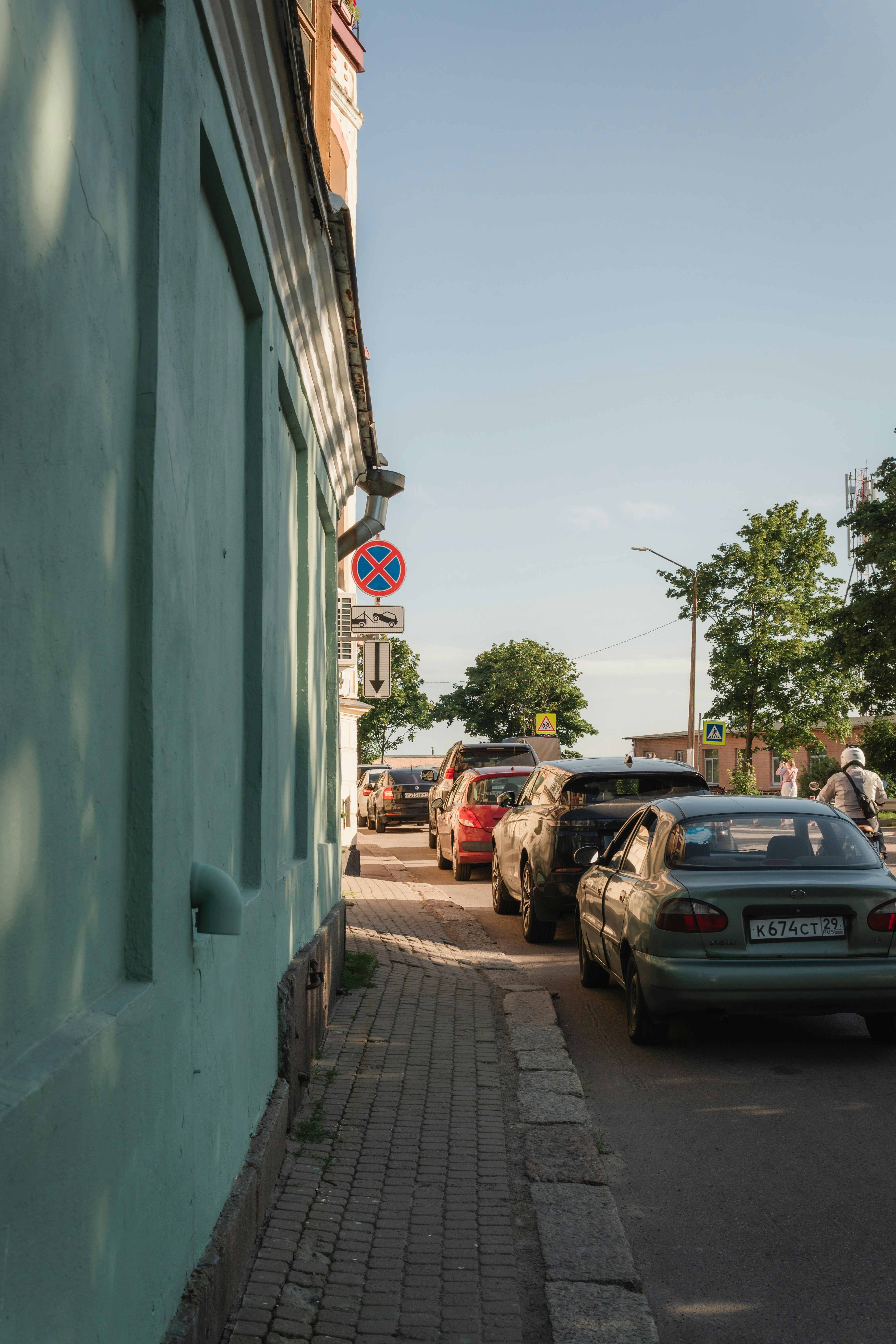 Curbside Corridor: Cars in the Sun Along a Turquoise Wall