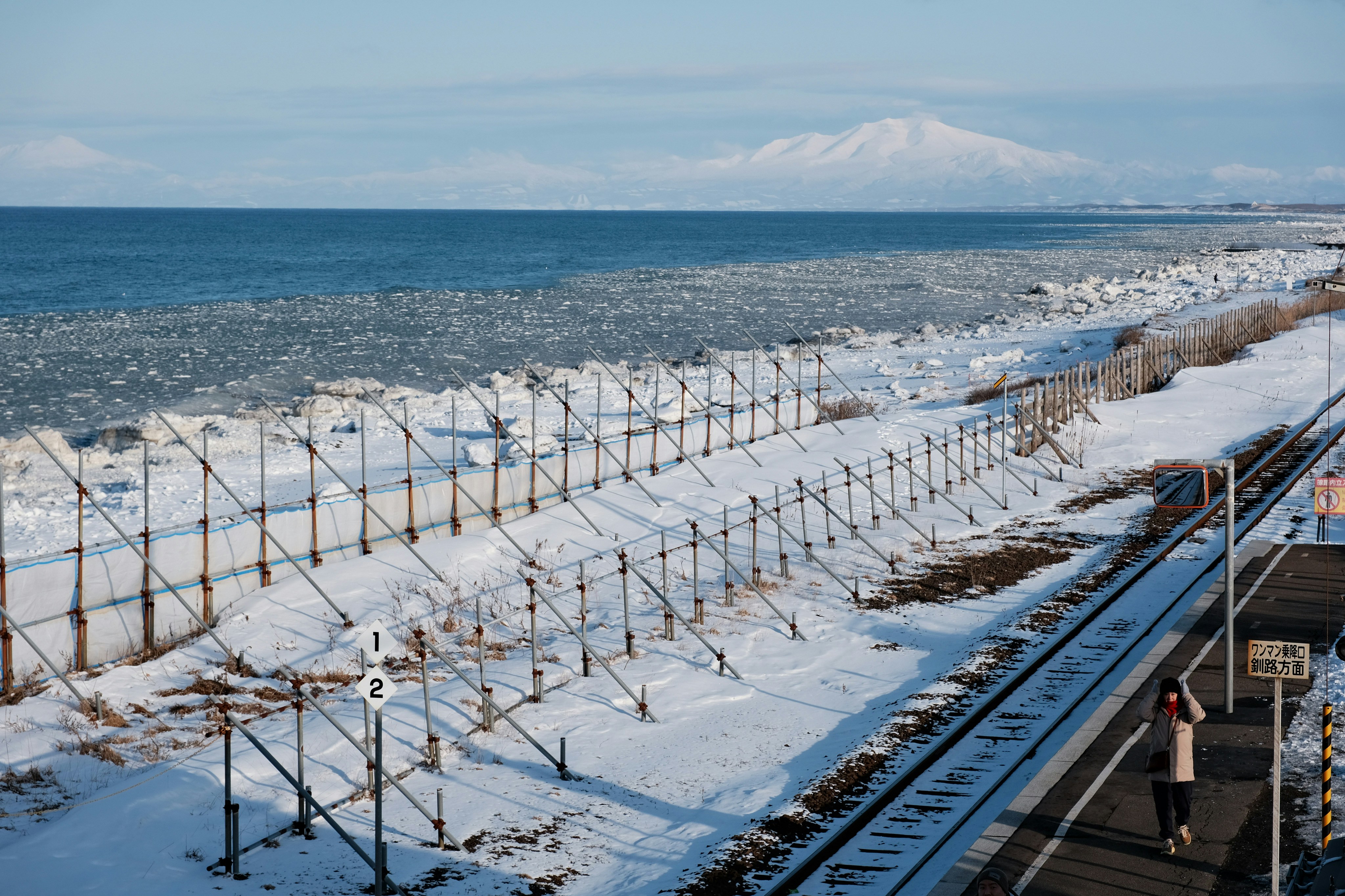 Snow-Capped Rails and a Lone Figure by the Sea
