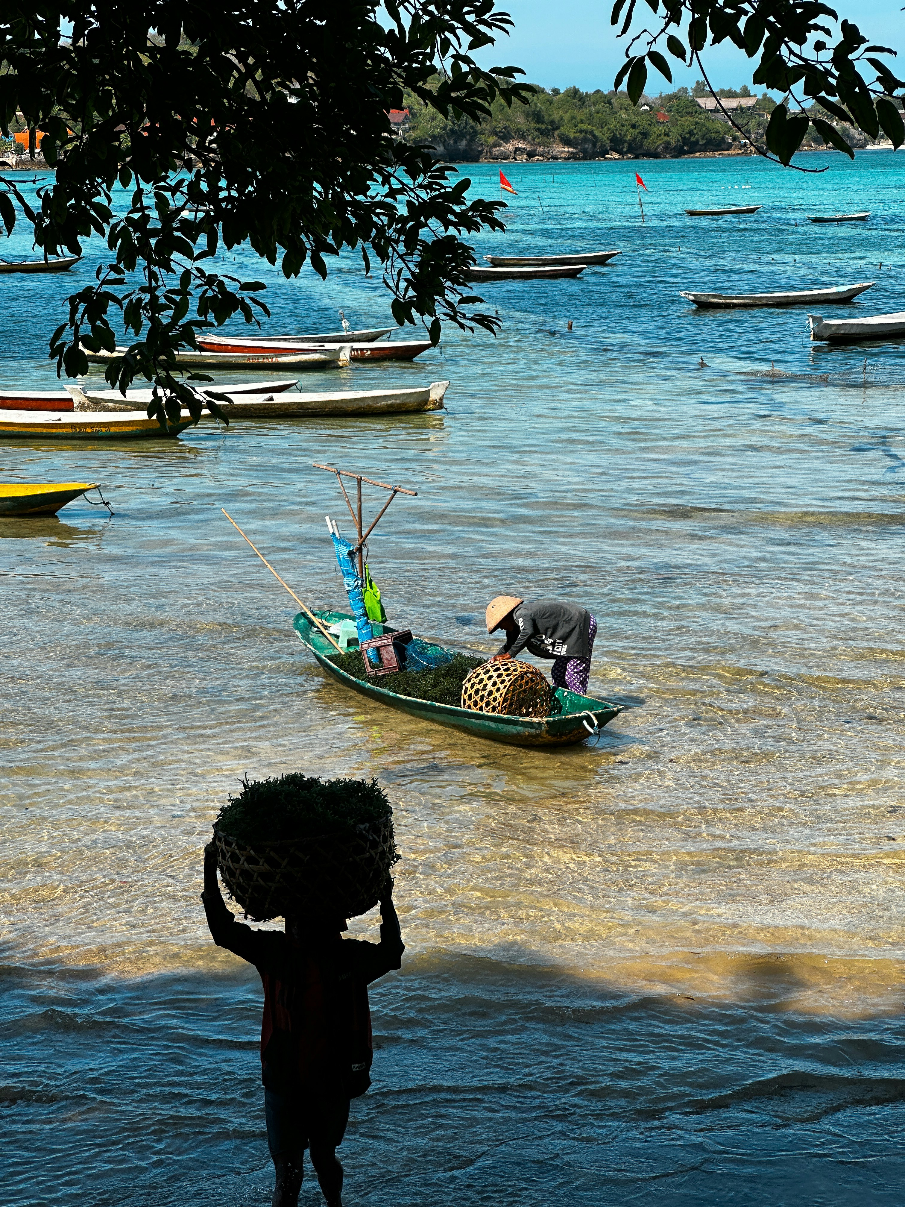 Basket-Bearer at the Tidal Threshold: Silhouette Amid Turquoise Waters