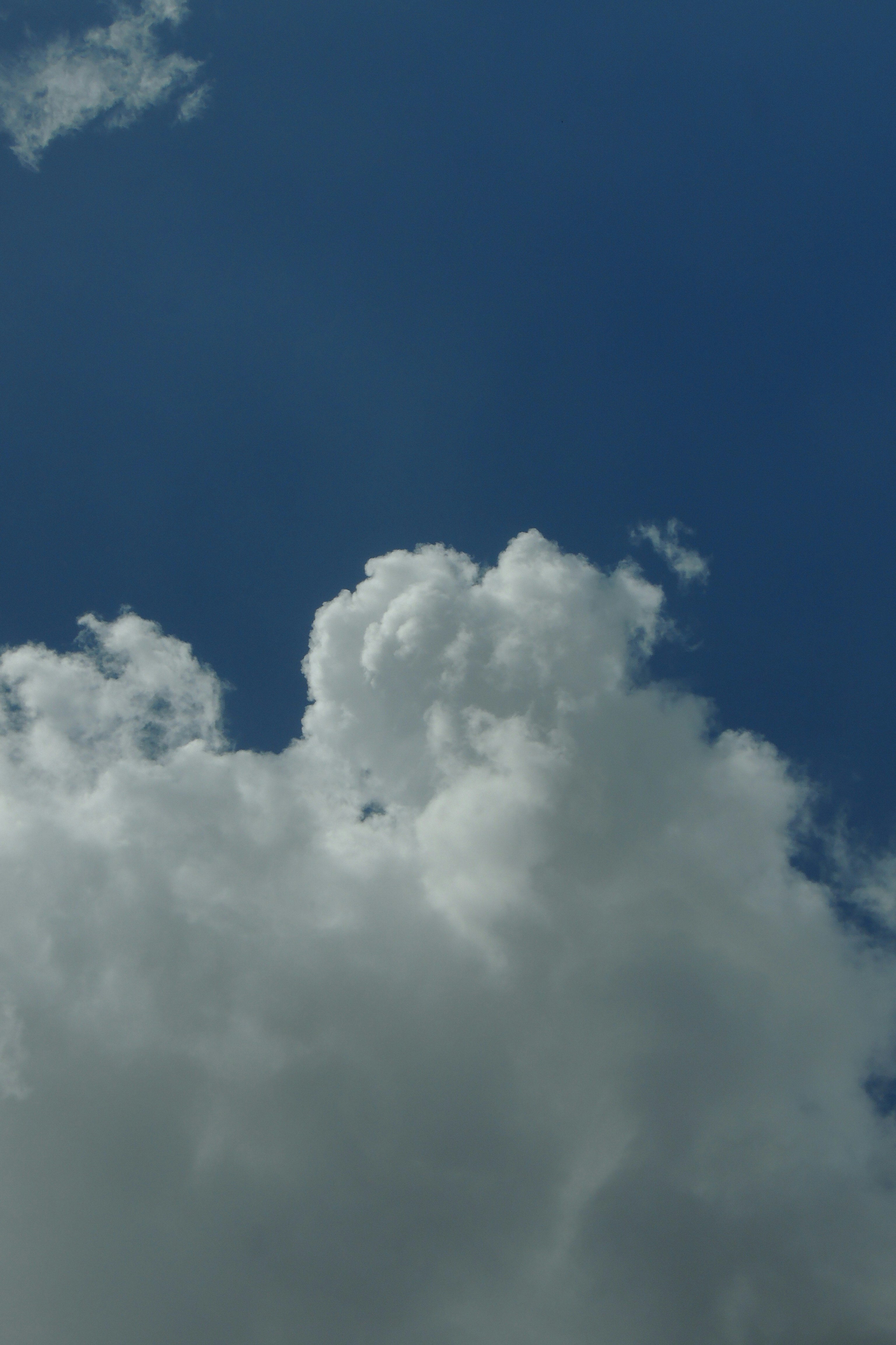 A plane flying through a cloudy blue sky