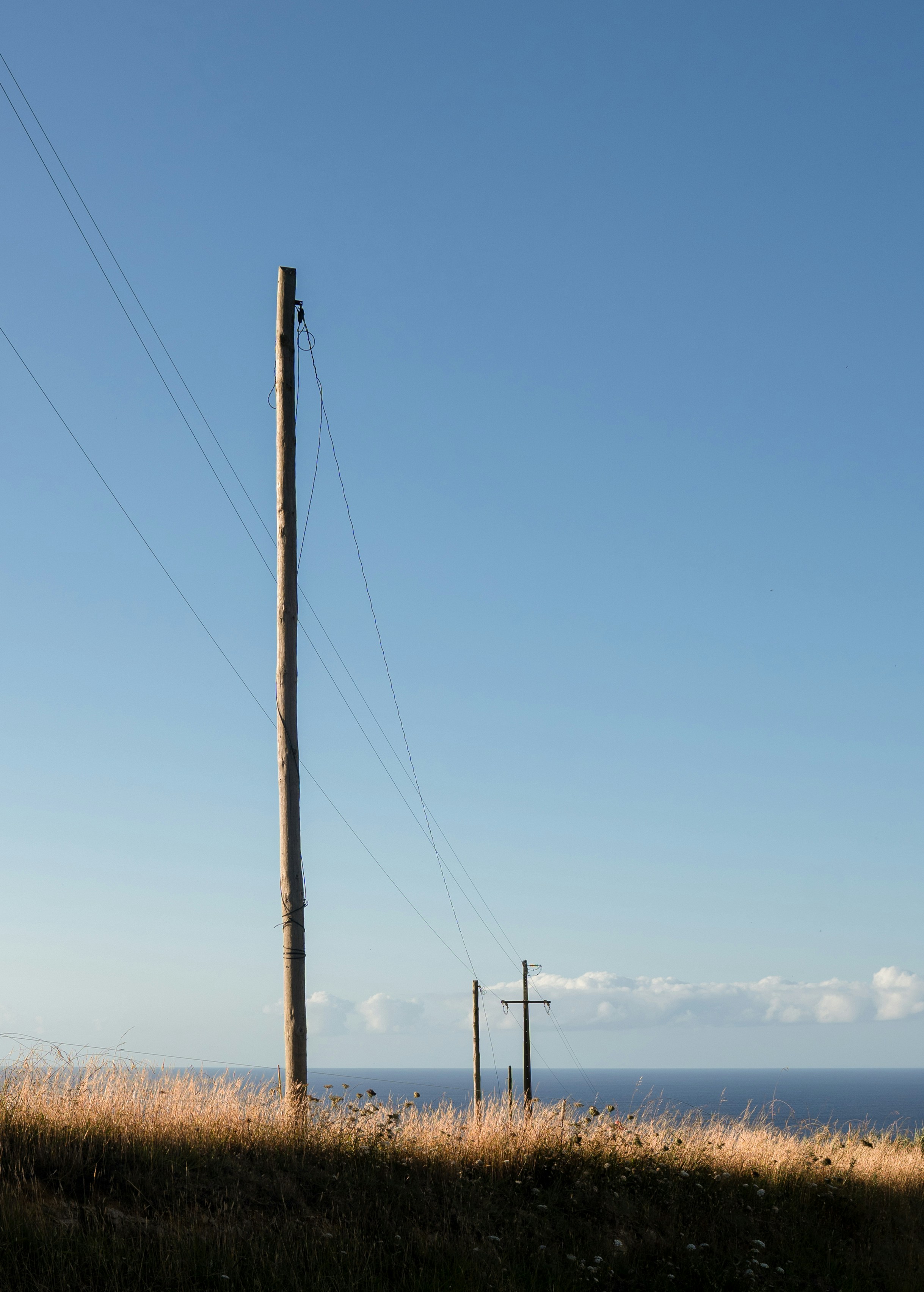 Lone Coastal Pole Tracing a Quiet Blue Horizon