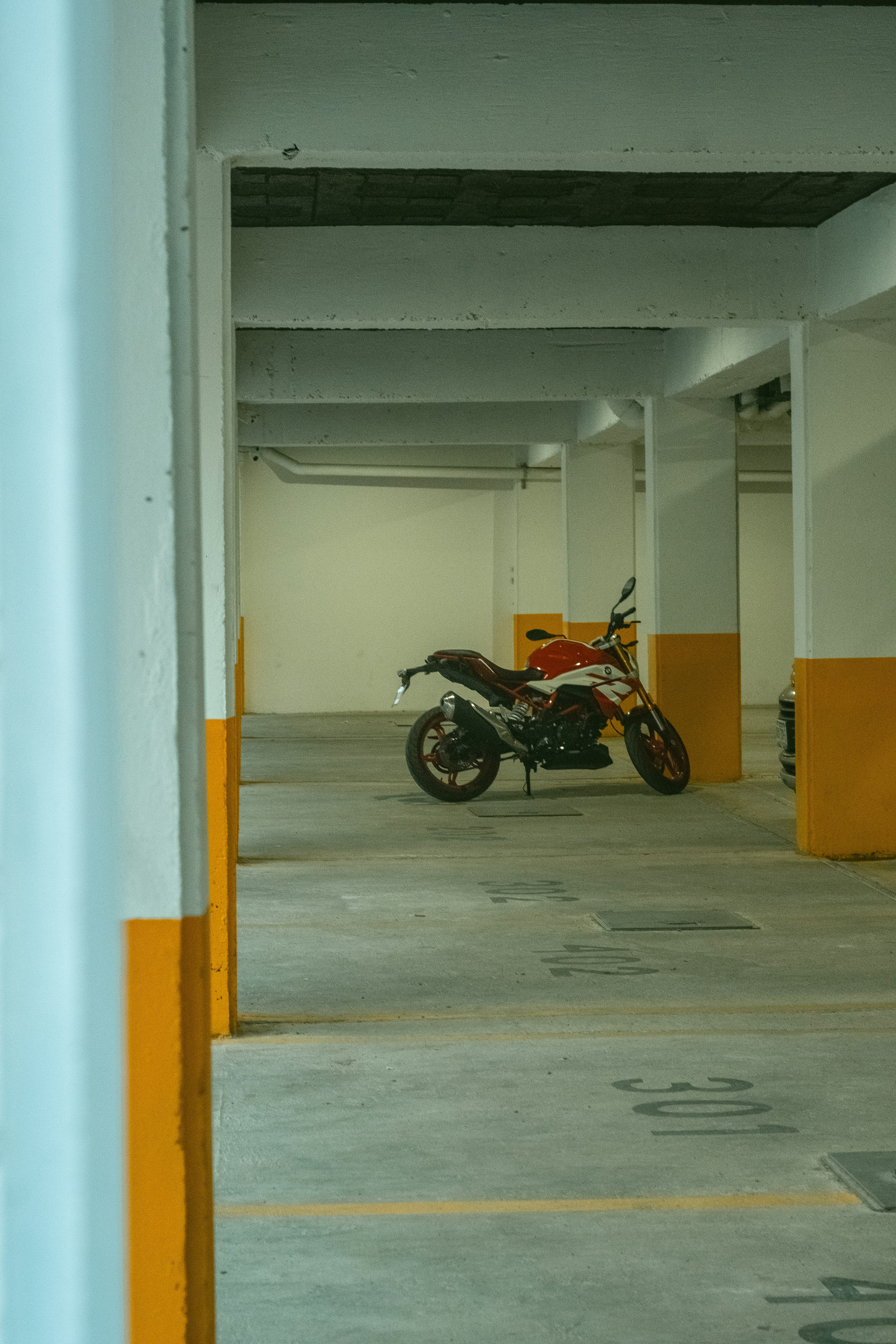 Red Sportbike Resting Between Orange Pillars in a Quiet Parking Garage