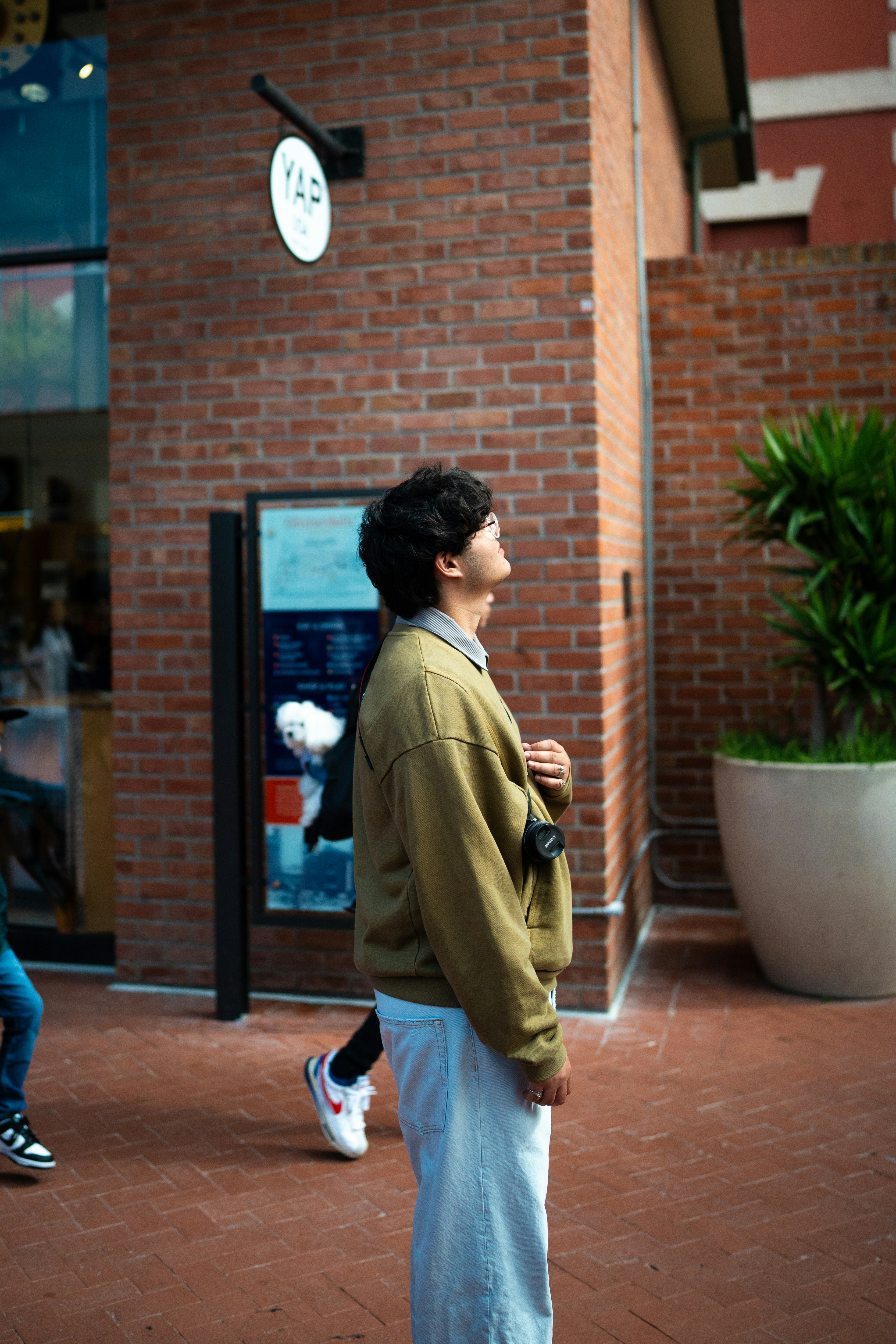 Pause Under the YAP Sign: Quiet Moment by the Brick Facade