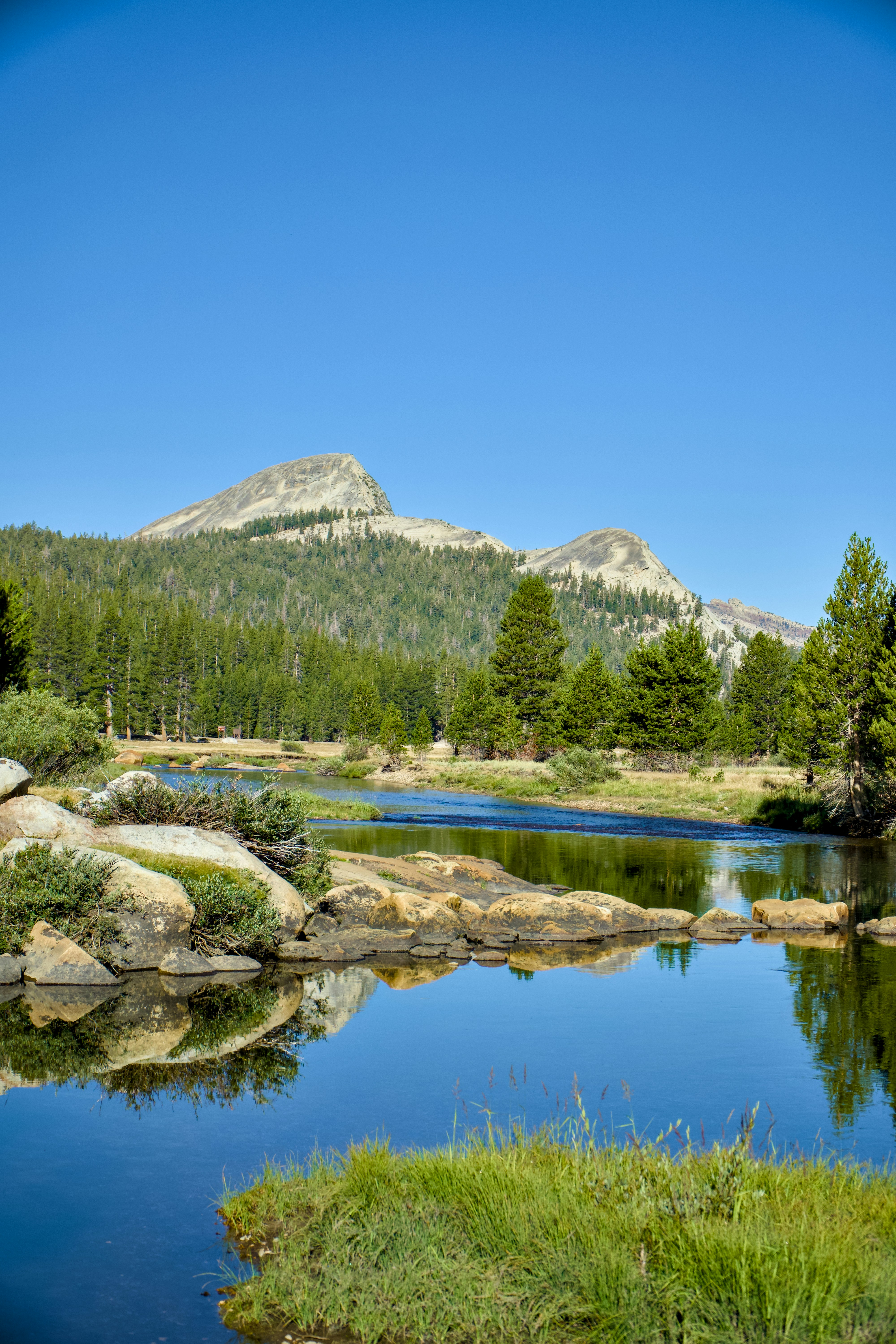A lake surrounded by rocks and trees with mountains in the background ...