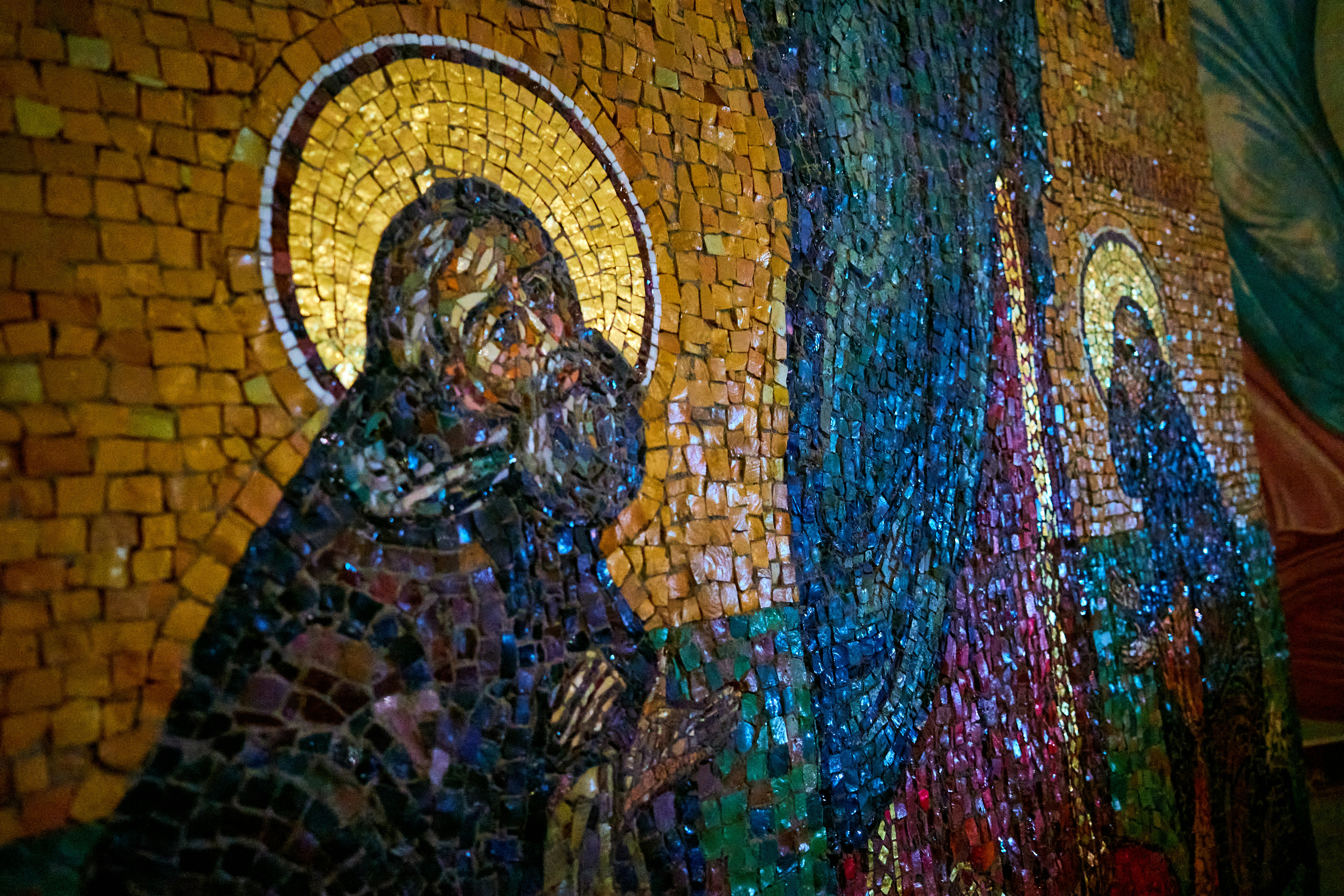 Colorful mosaic depicting a saint with a golden halo, showcasing intricate details and vibrant hues.