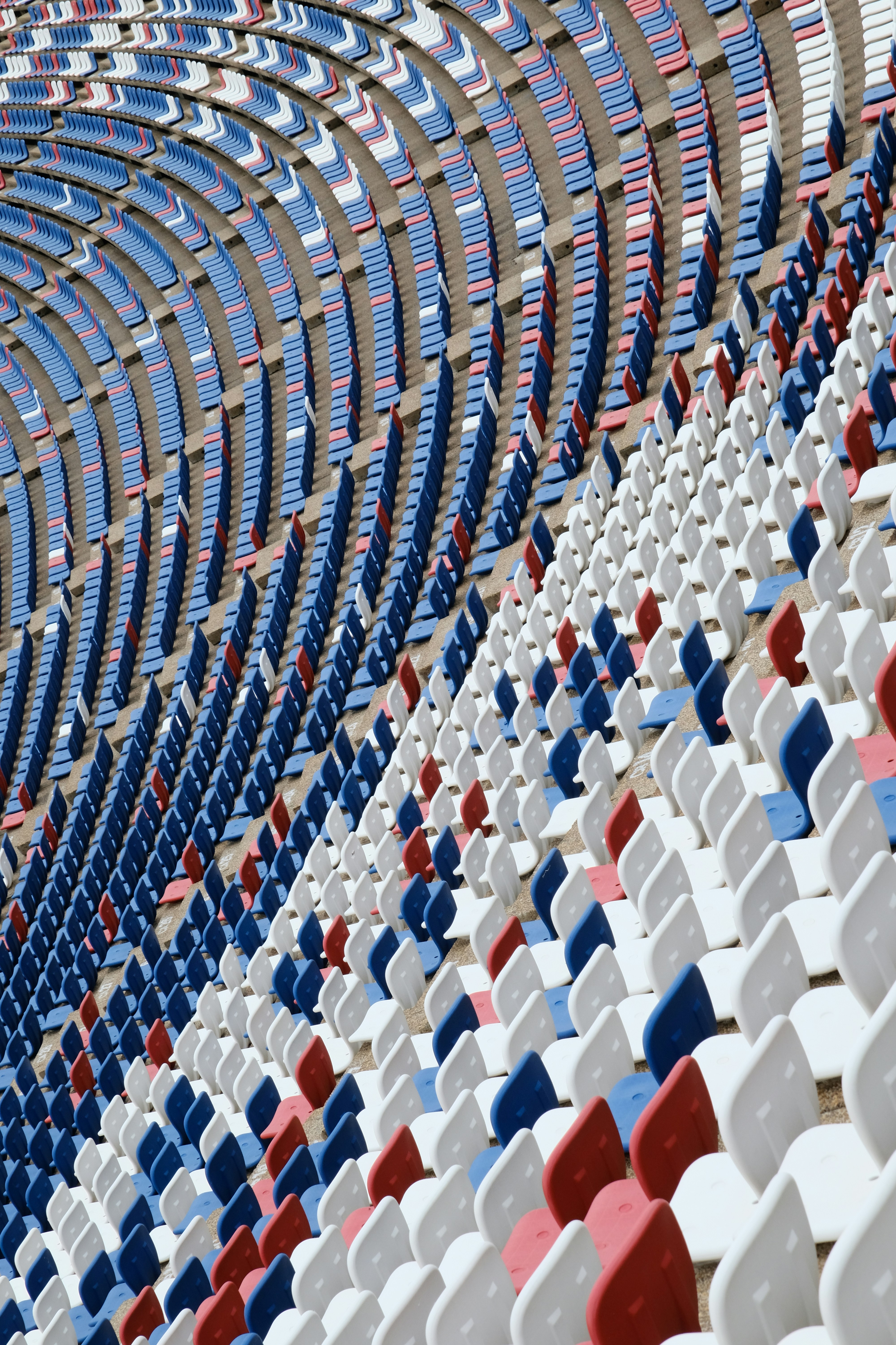 Rhythmic Tiers: Multicolor Stadium Seats in a Curving Canopy