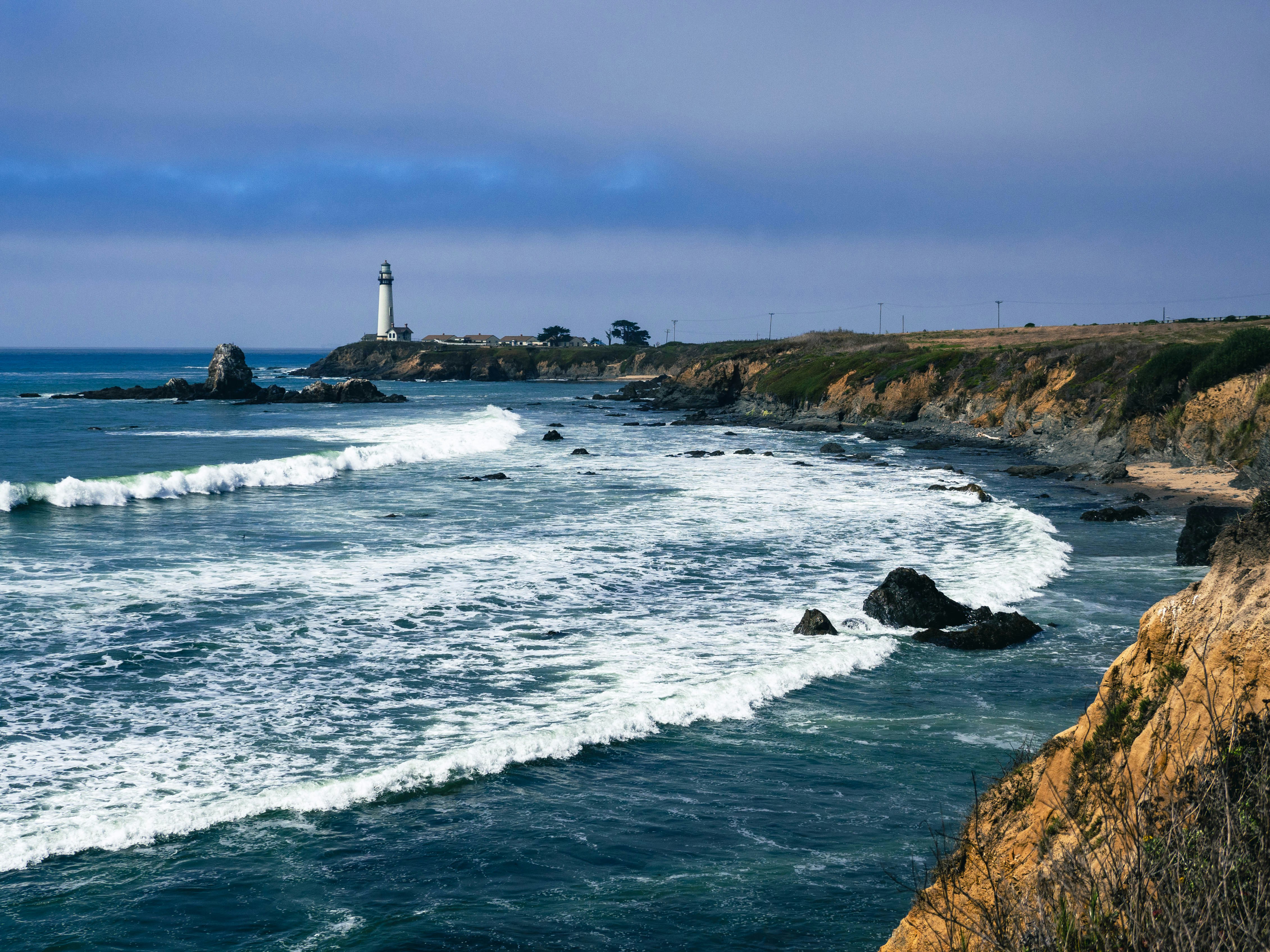 Beacon on the Bluff: Salt-Sprayed Cliffs and a Quiet Sea