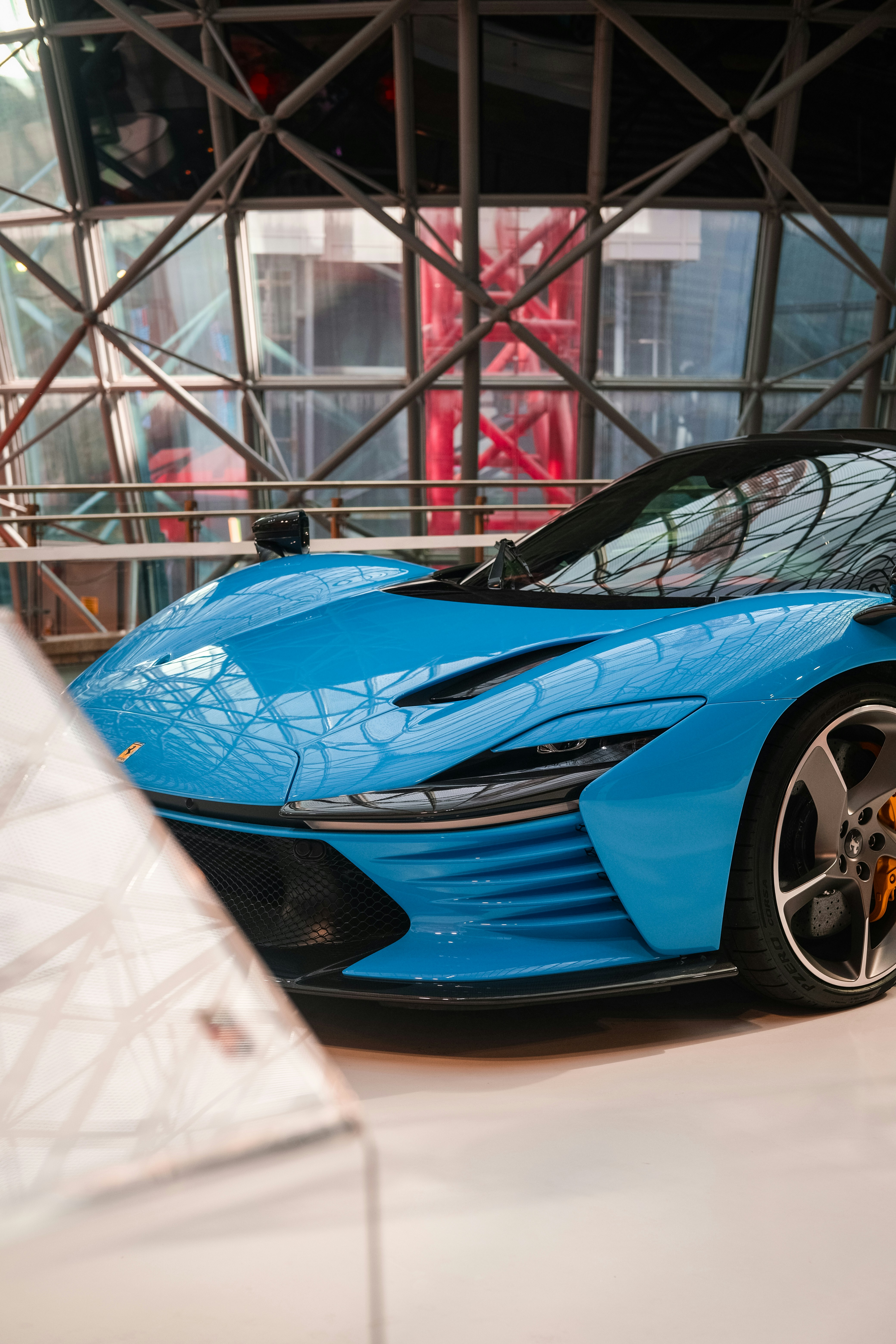 Azure velocity under glass: a blue supercar framed by lattice reflections