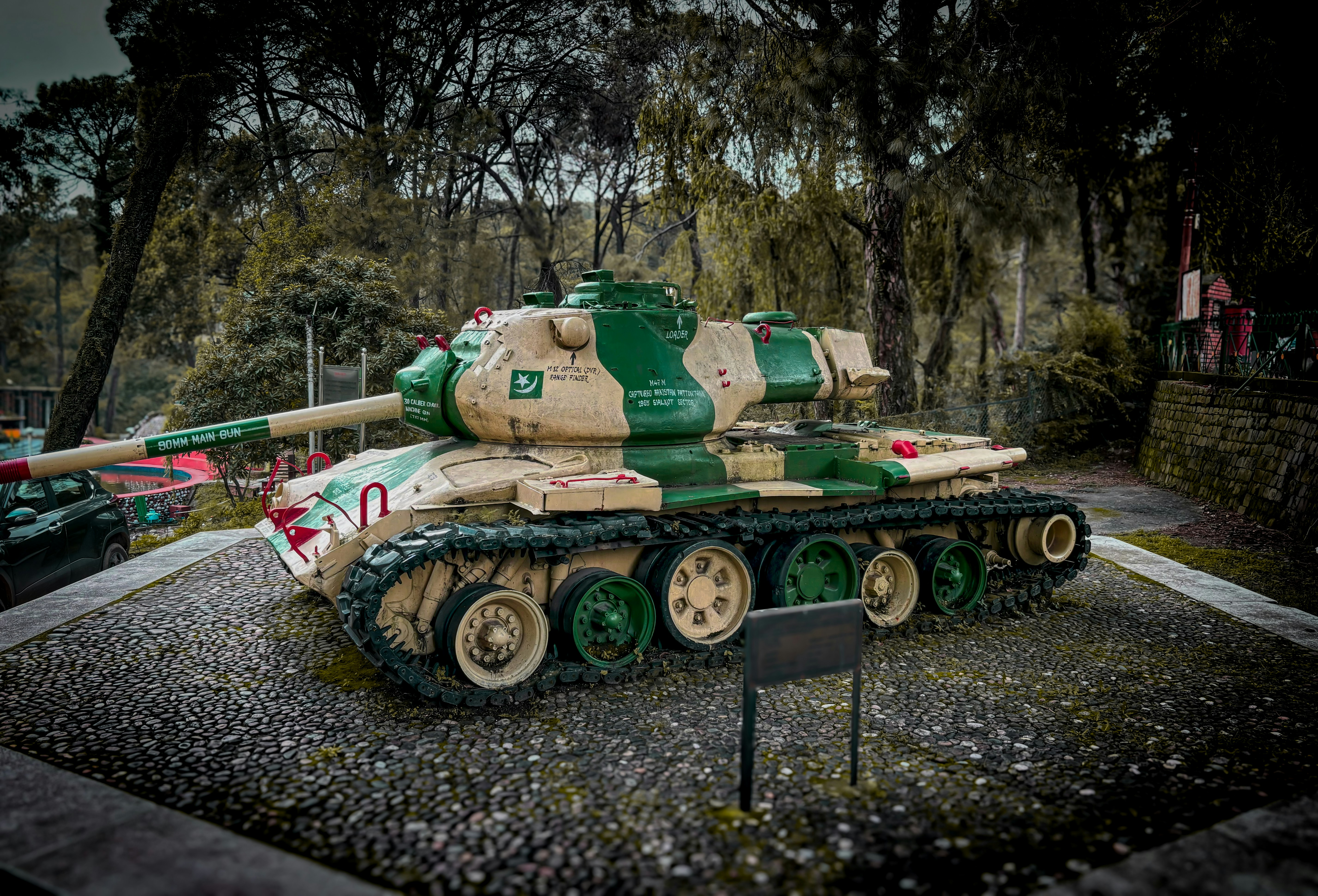 A green and white tank sitting on top of a gravel field photo – Free ...