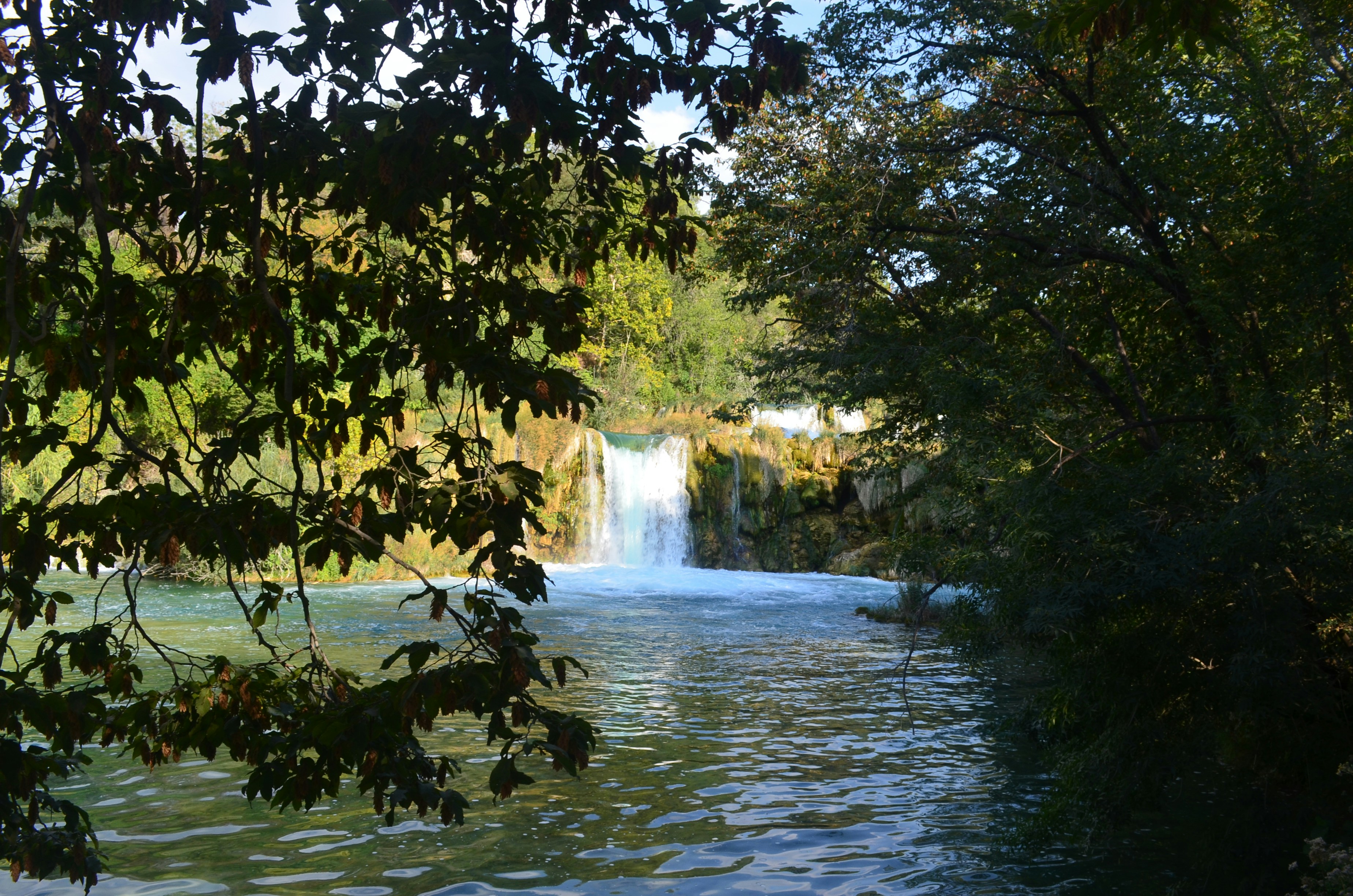 A view of a waterfall through some trees photo – Free Krka national ...