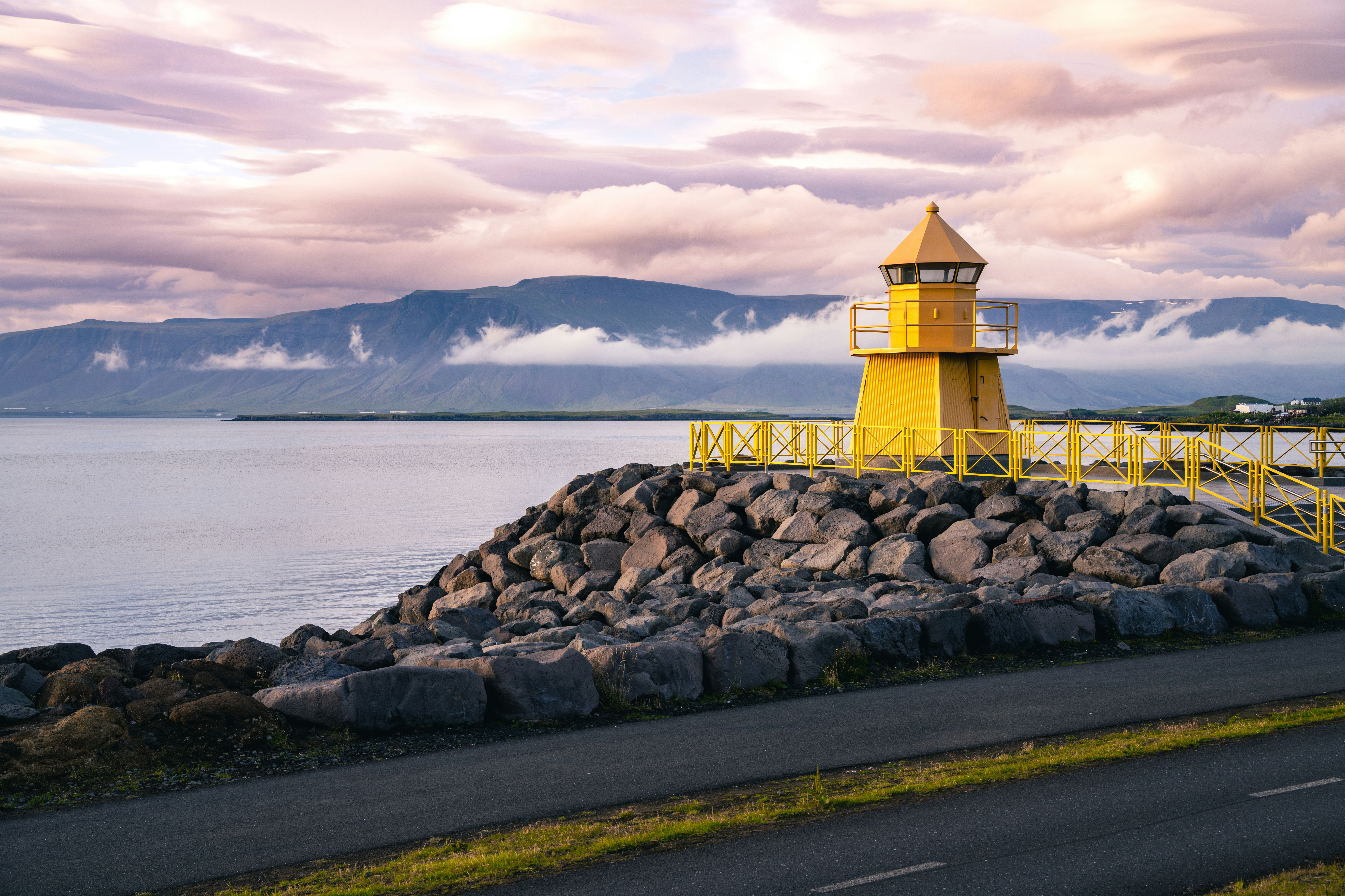 A yellow lighthouse sitting on top of a rocky shore photo – Free ...