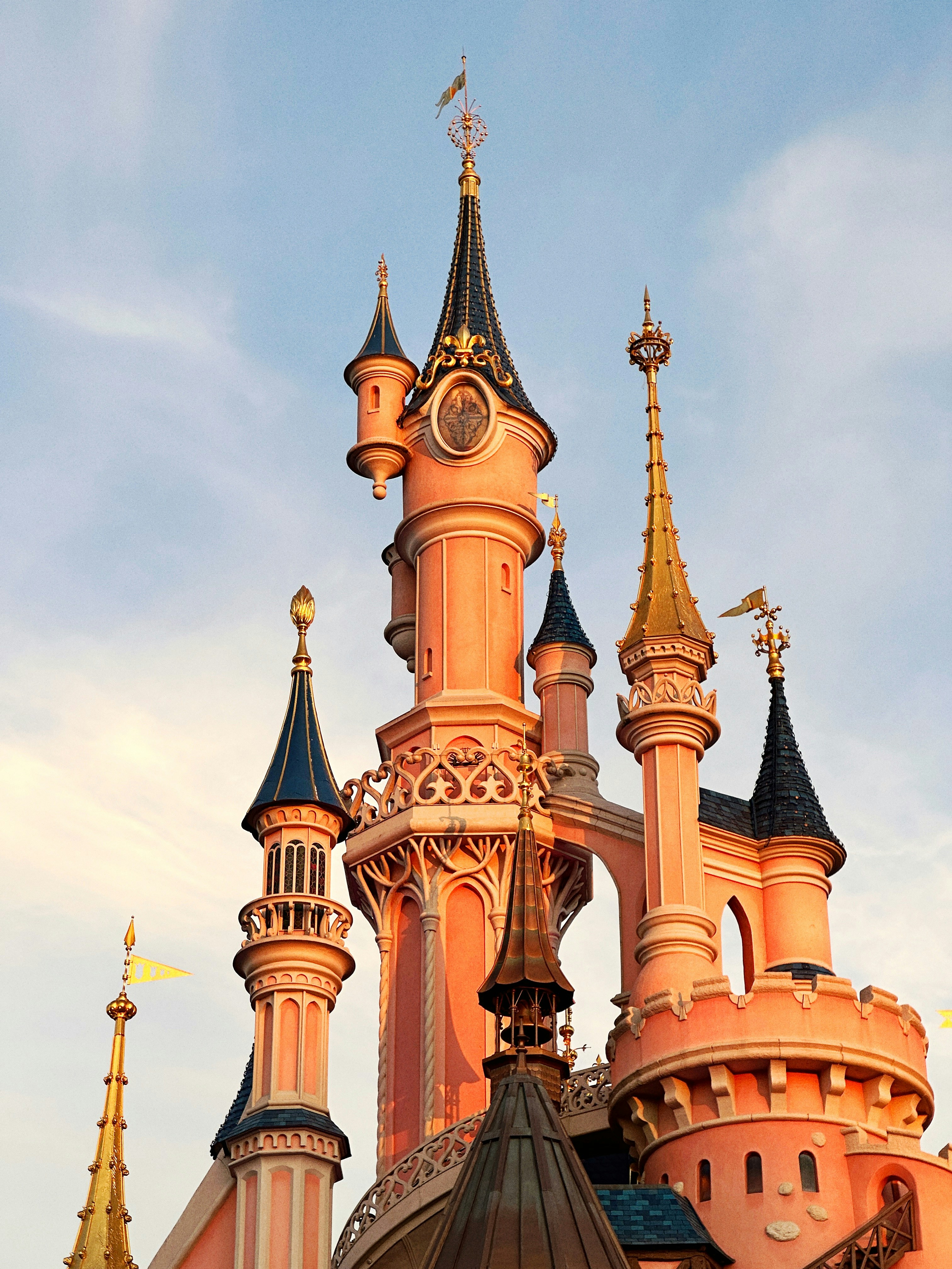 A large pink castle with a clock on it's side photo – Free Disneyland ...