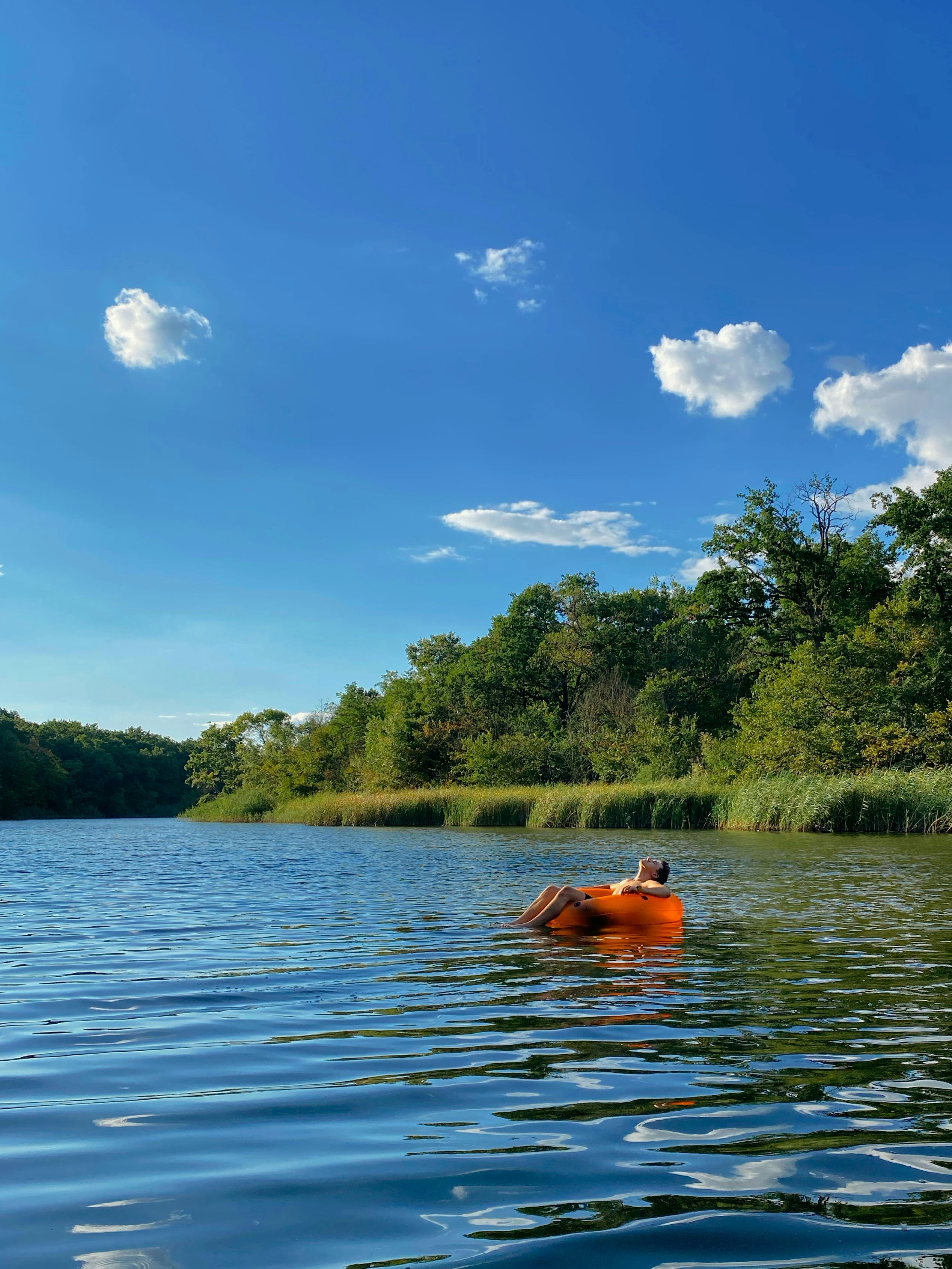 A person in an orange raft floating on a lake