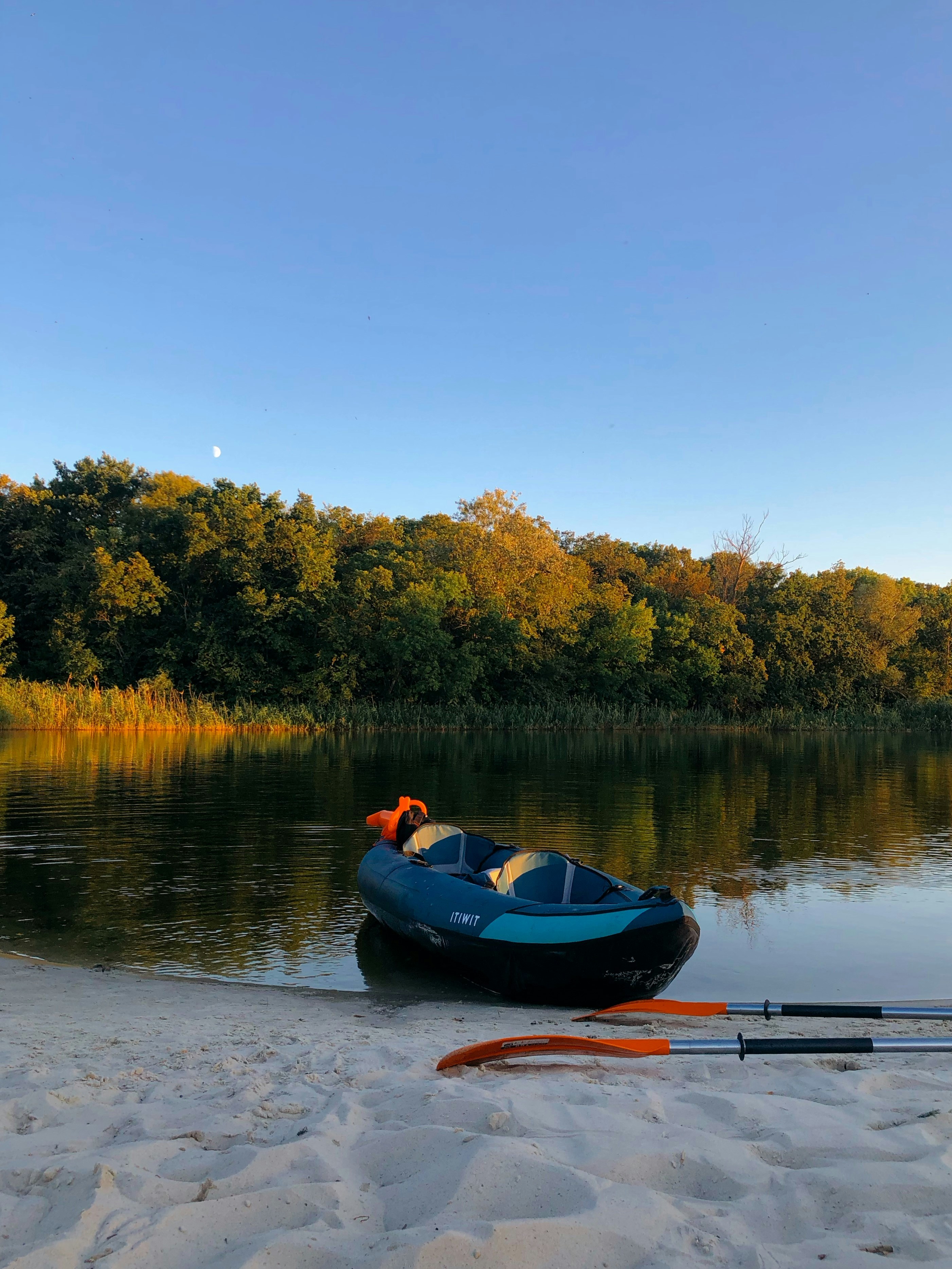 Blue inflatable boat resting on a tranquil lakeshore at golden hour