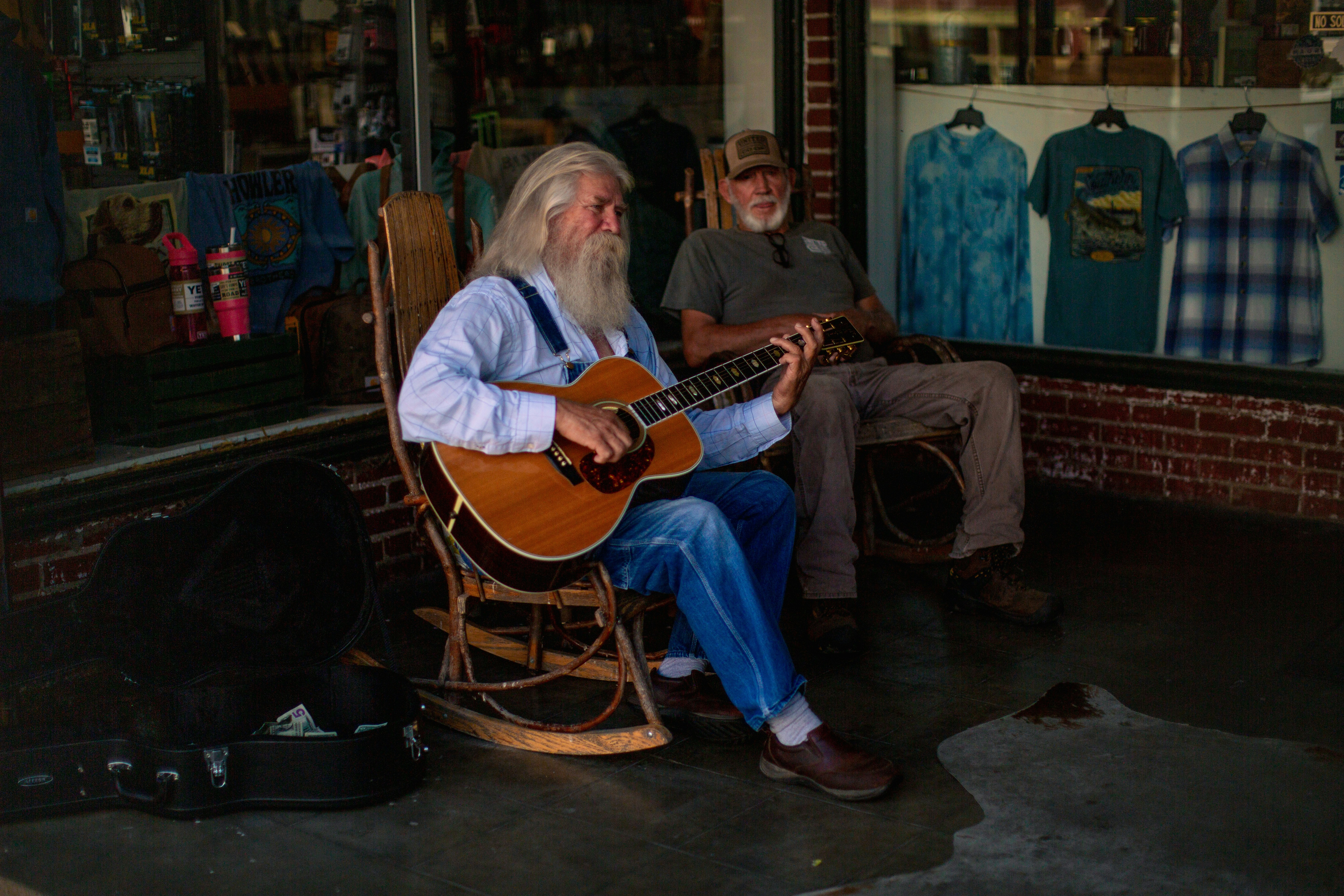 A man sitting in a rocking chair playing a guitar photo – Free Man ...
