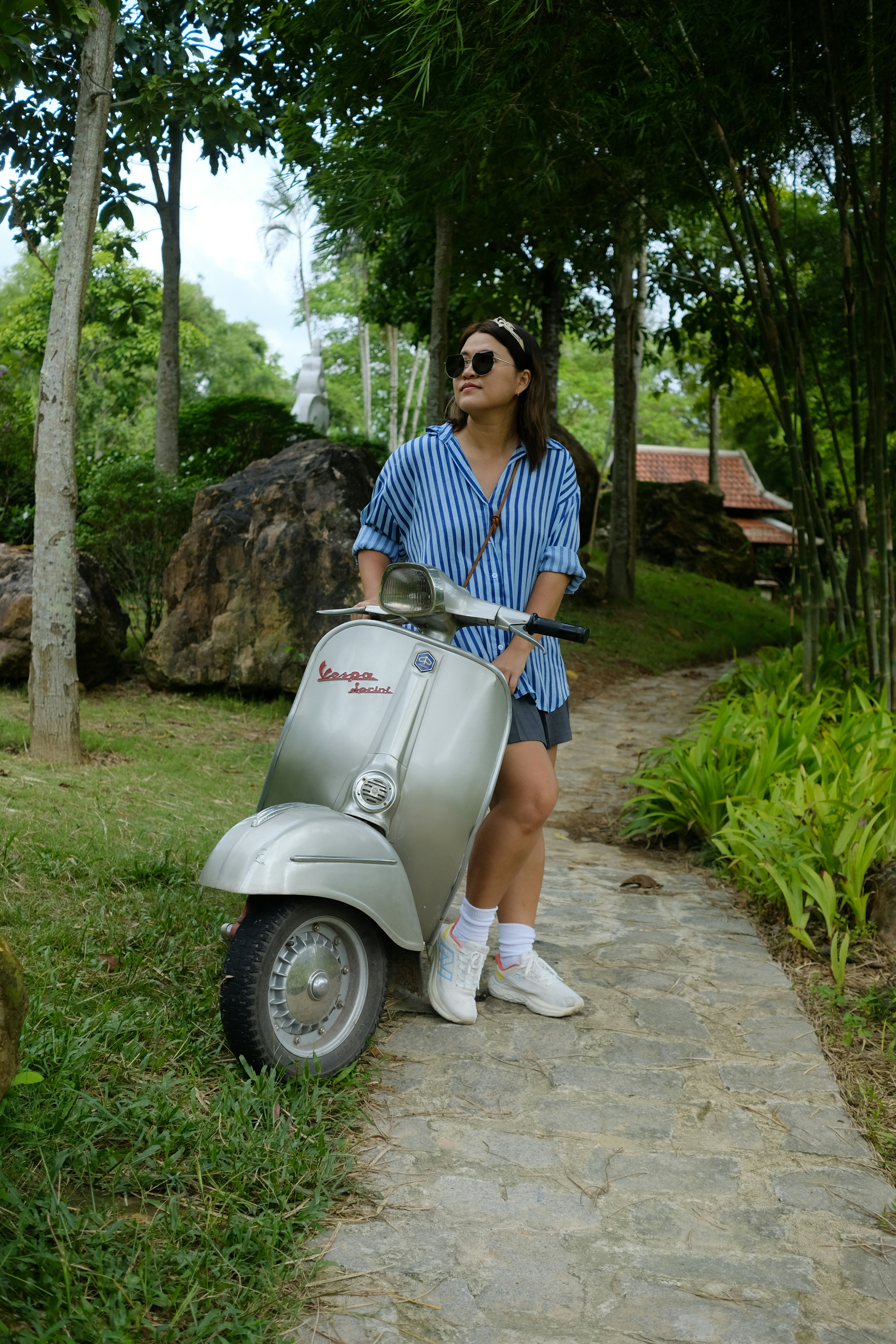 Lady with a Silver Vespa in a Lush Garden Path