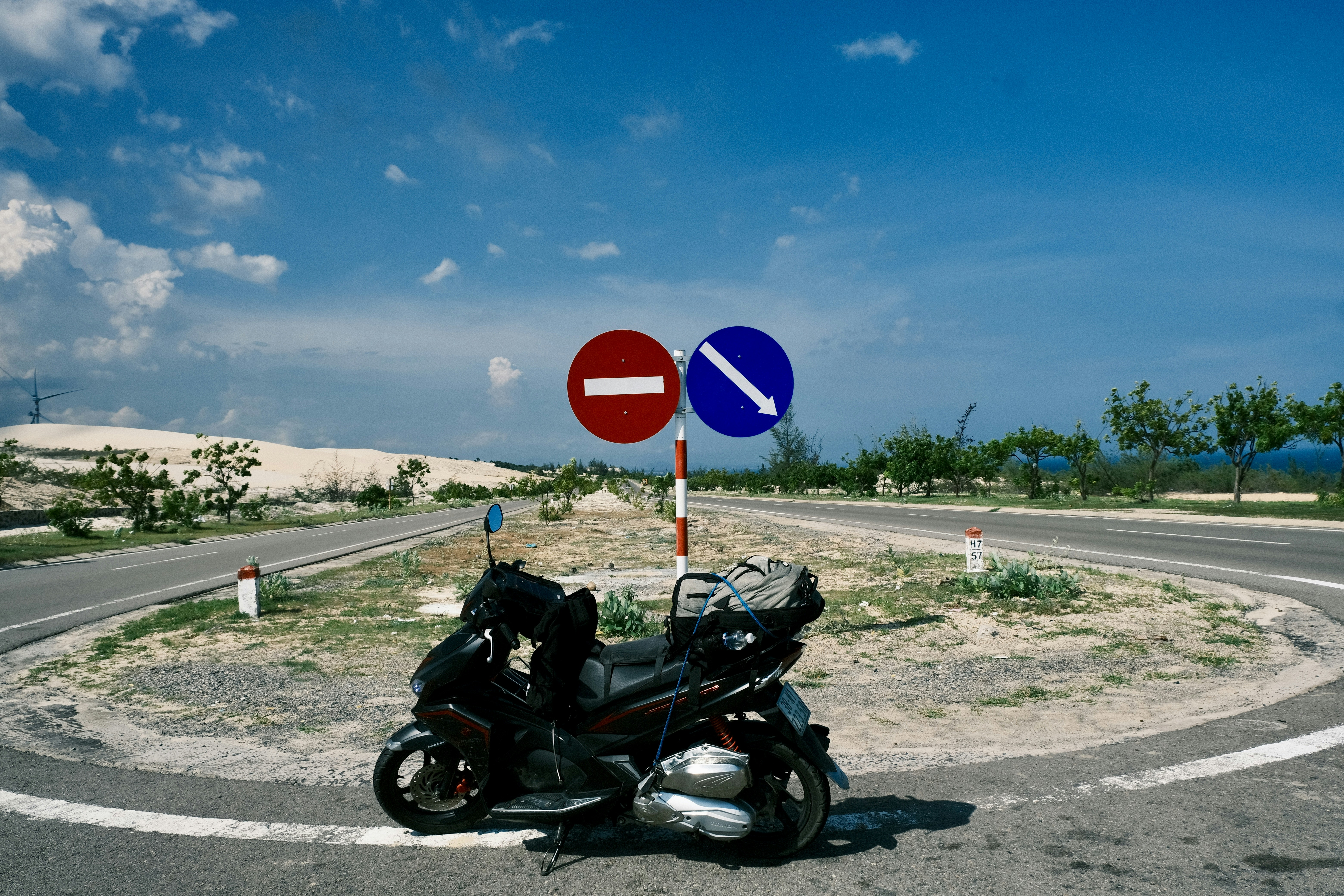 Roundabout Rendezvous: Motorcycle Nestled Beneath Red and Blue Signals