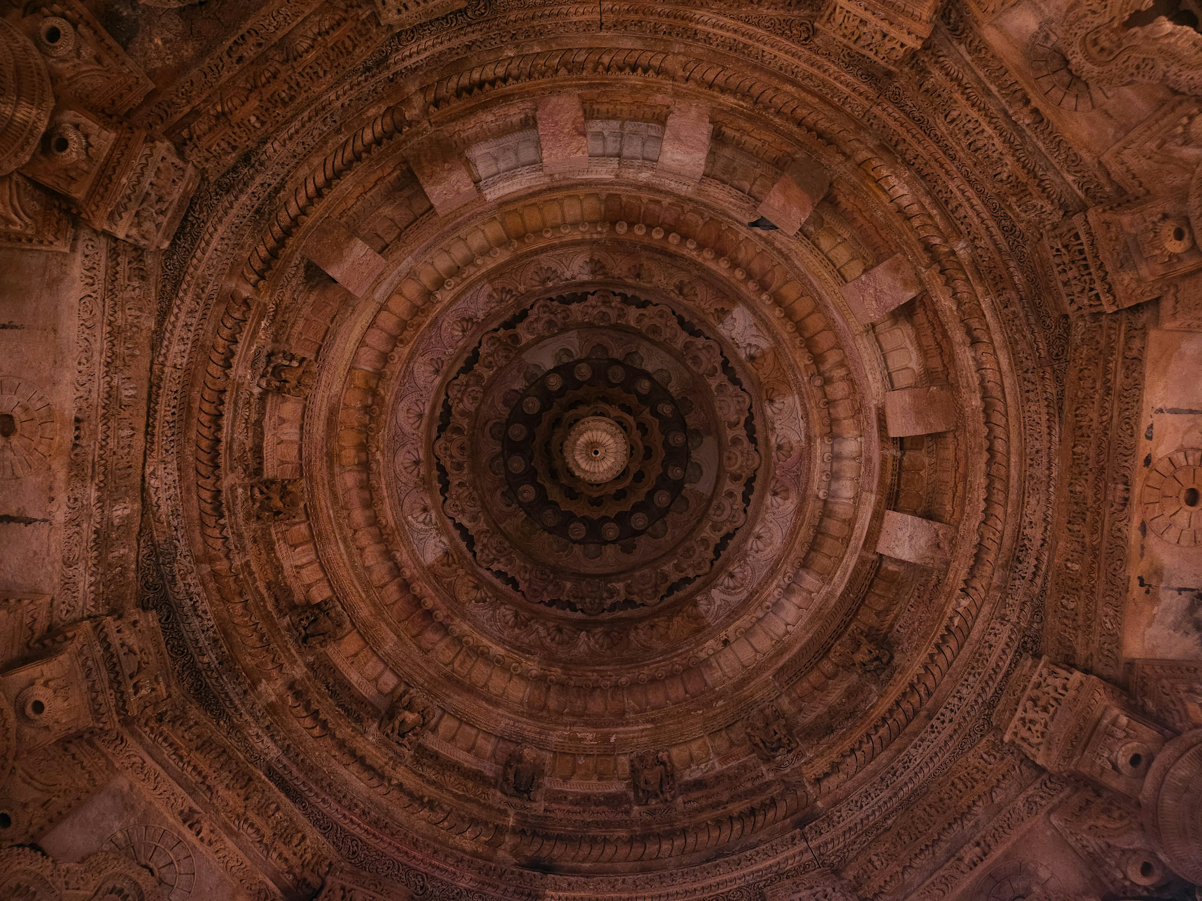 Ornate circular dome interior with concentric rings and carved stonework, bathed in warm amber lighting.