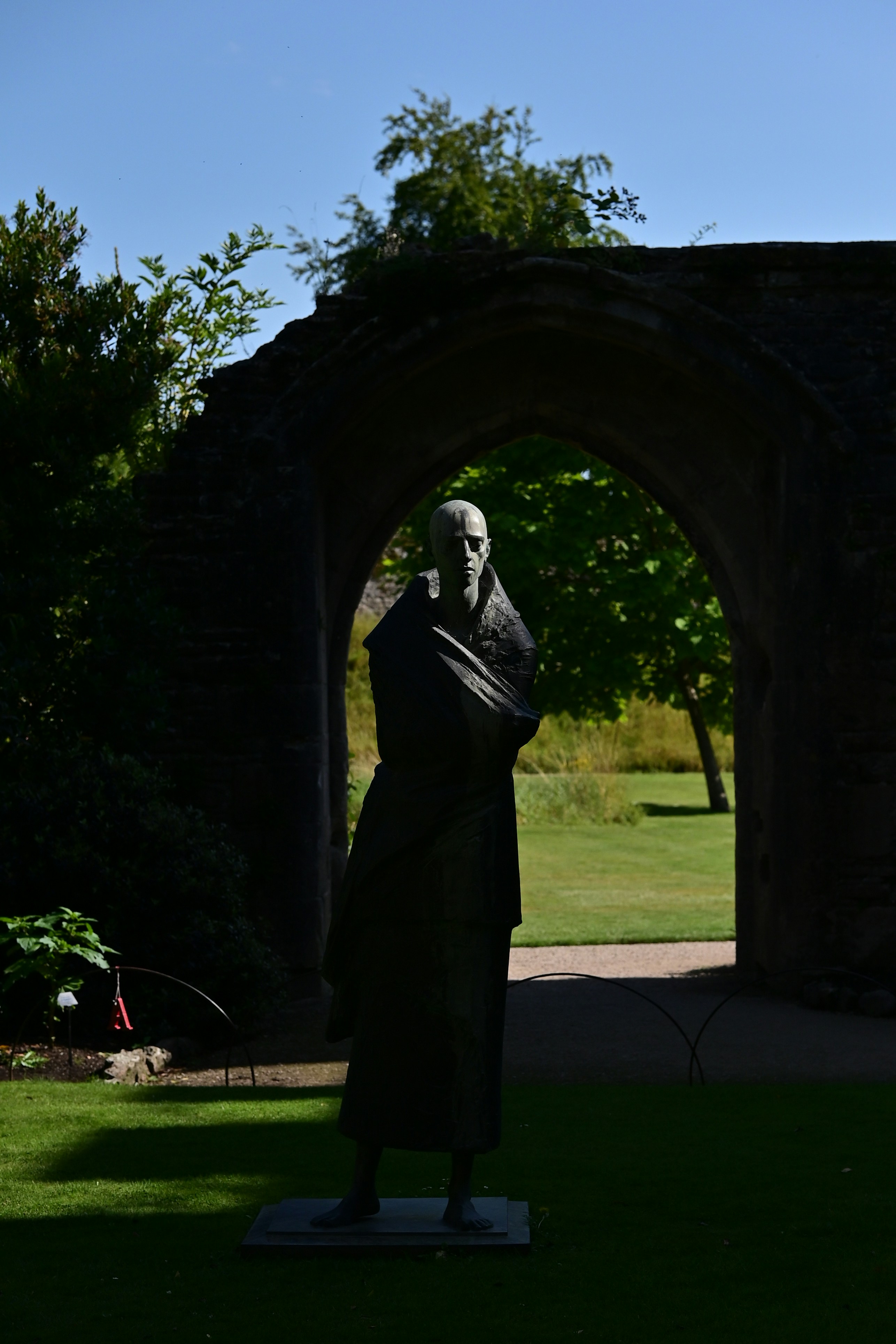 Archway Sentinel: A solitary statue framed in shadow and green light