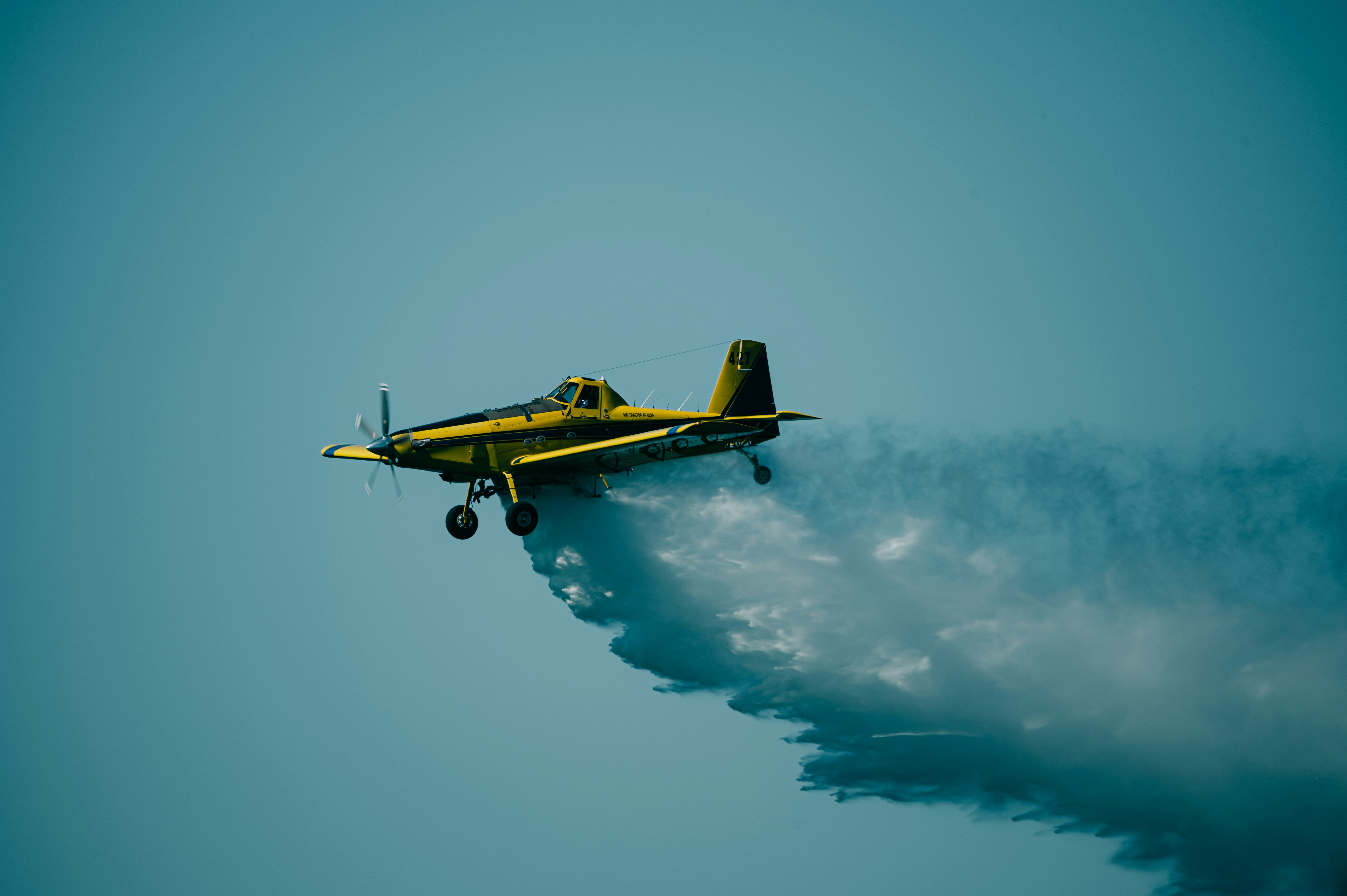 A small yellow plane flying through a blue sky photo – Free Animal ...