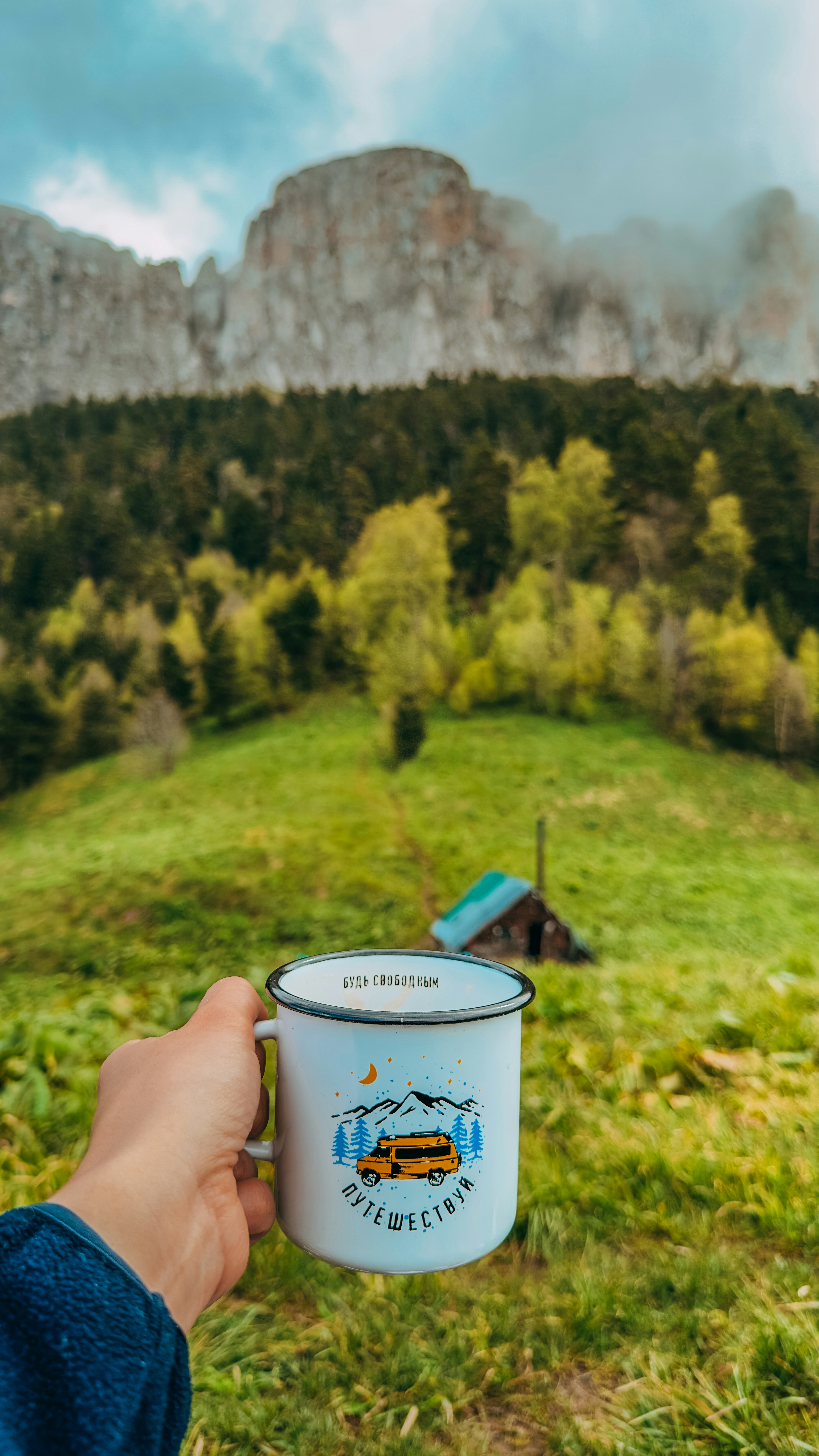 Alpine Brew in Focus: A Hand-Held Mug Framing a Misty Valley