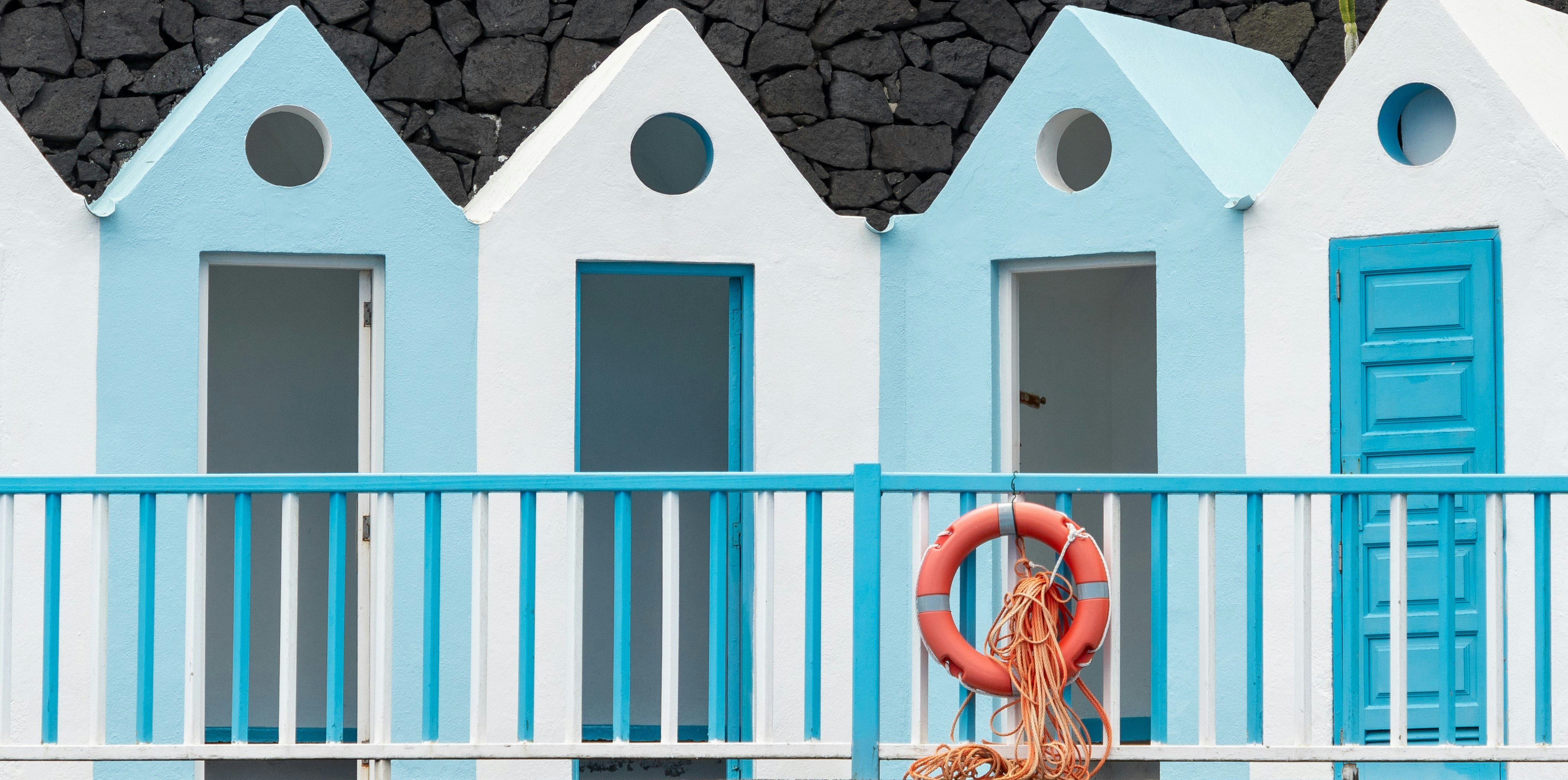 A row of beach huts with blue doors and windows photo – Free Formen ...