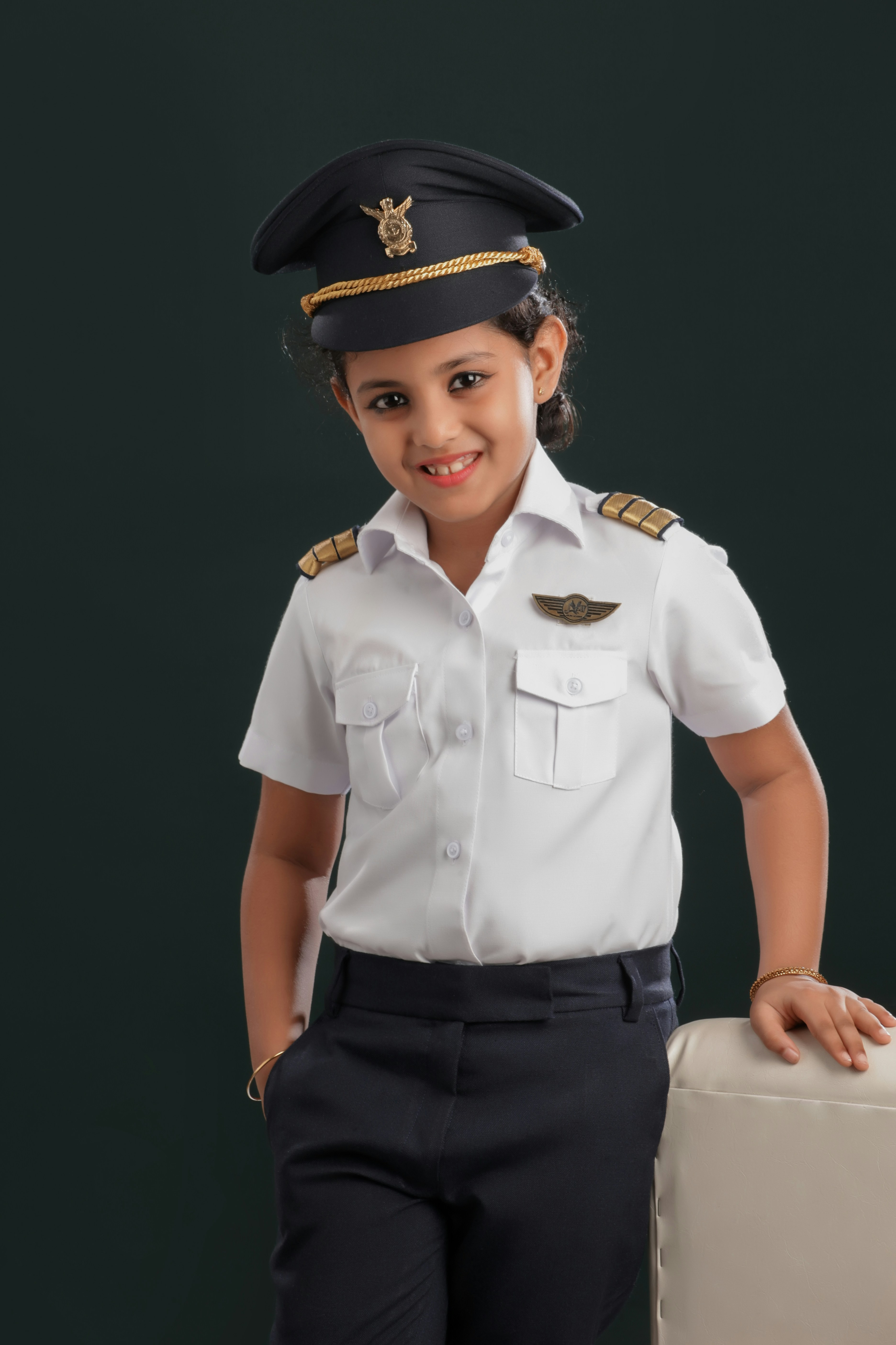 Young pilot in white shirt and cap standing beside a chair