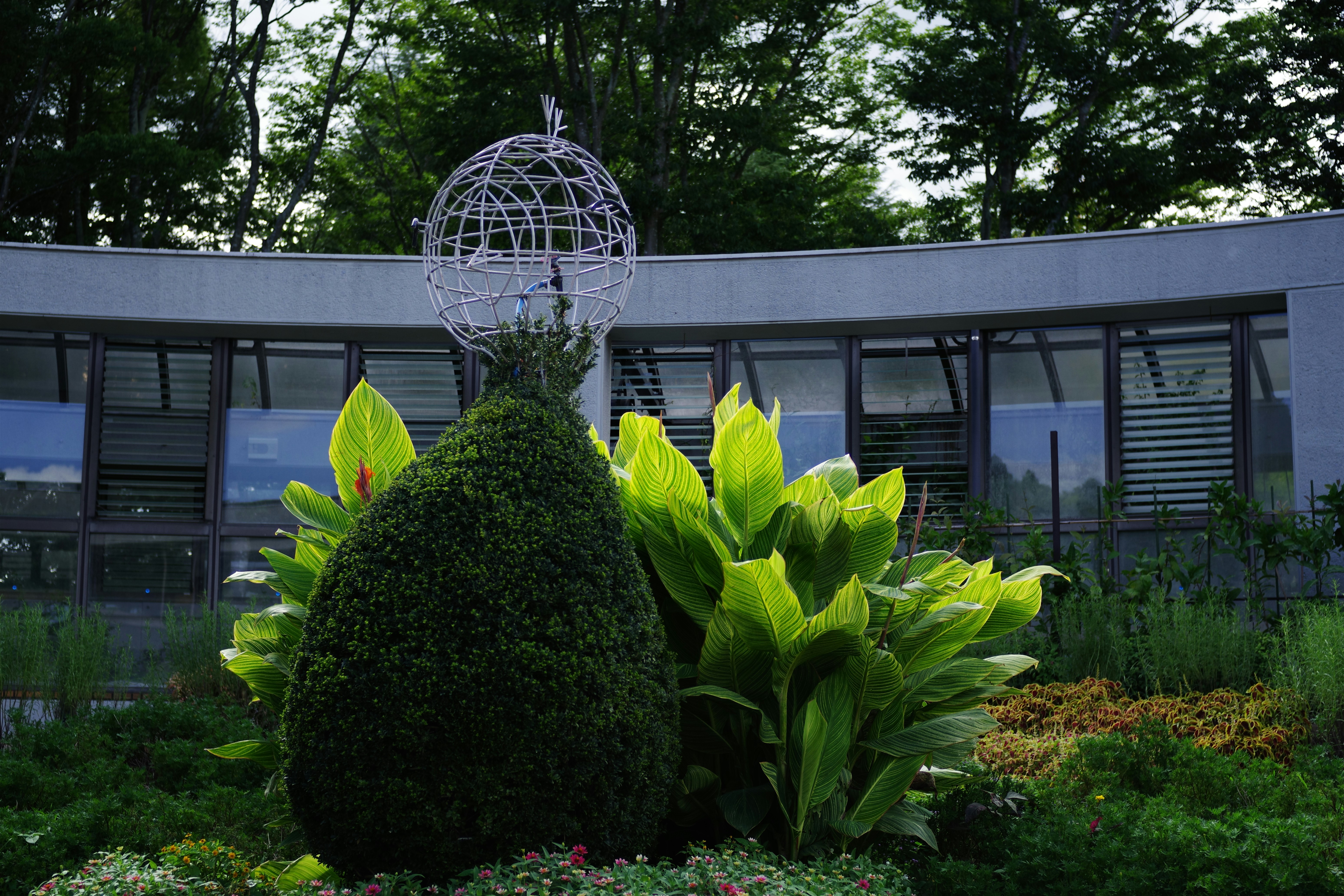 Globe Crown: A Wire-Sphere Sculpture Rising from a Verdant Cone in a Modern Courtyard