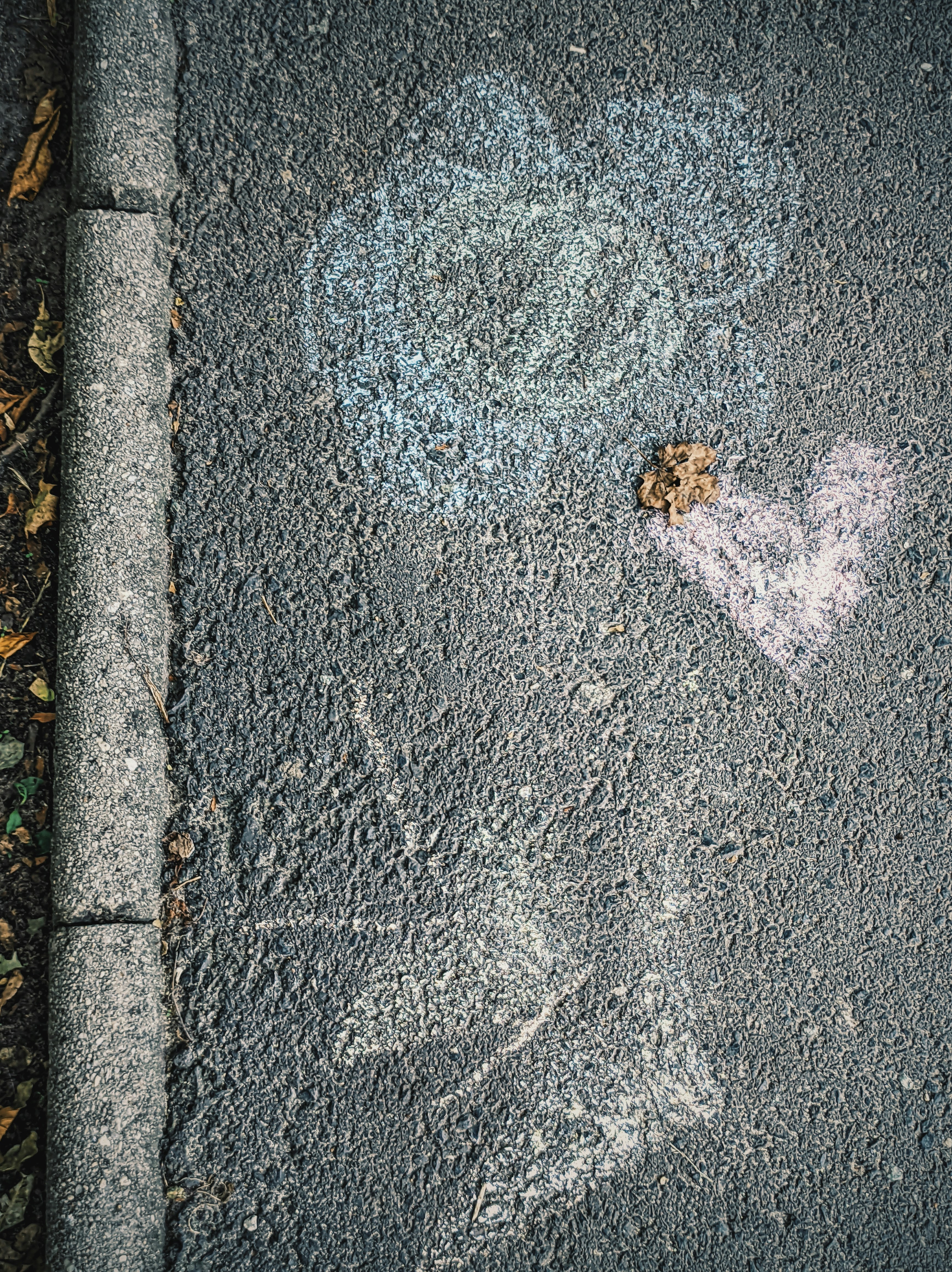 A heart drawn on the ground next to a curb