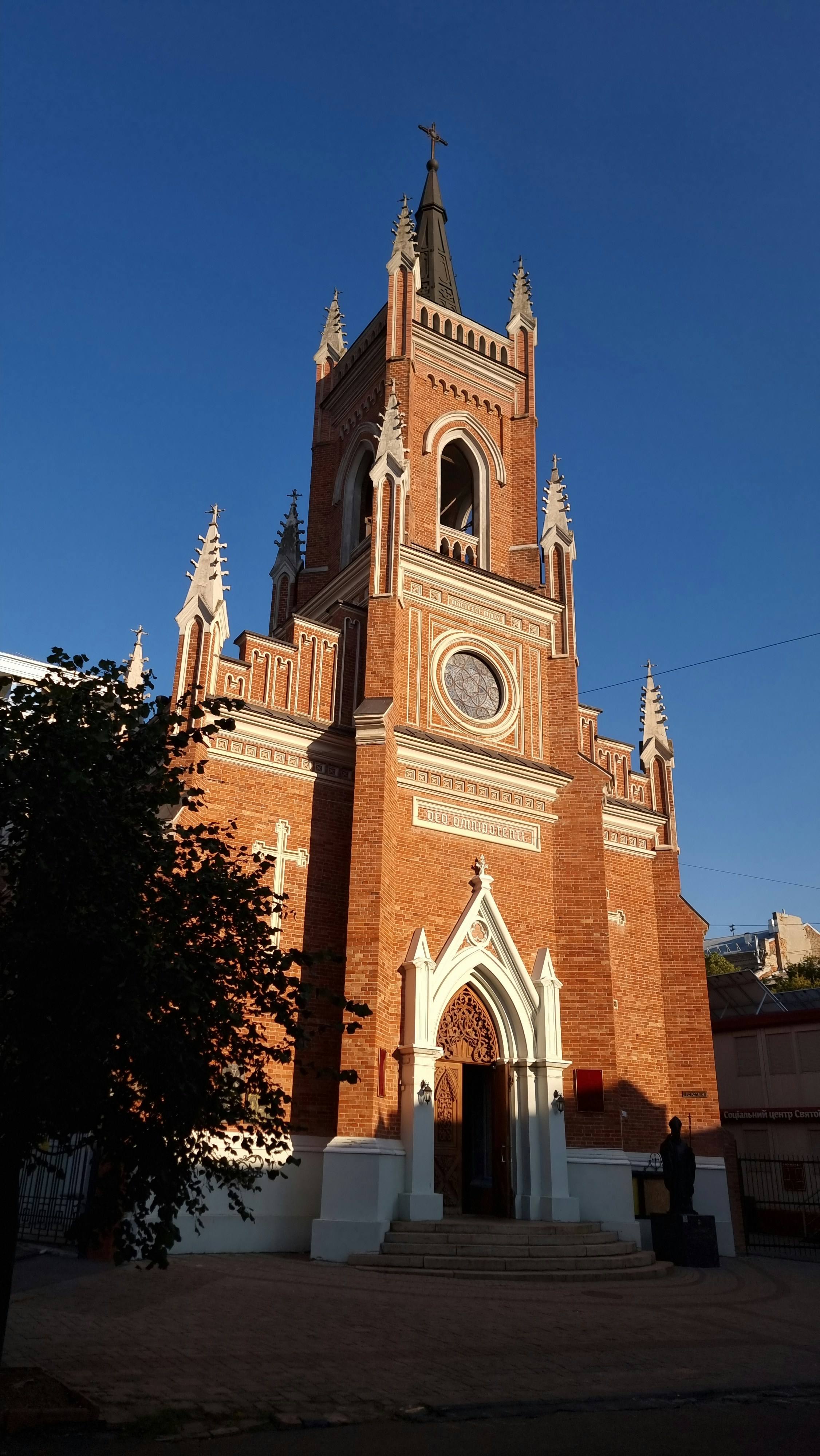 Blue-Sky Cathedral: Sunlit Brick Tower with White Gothic Spires