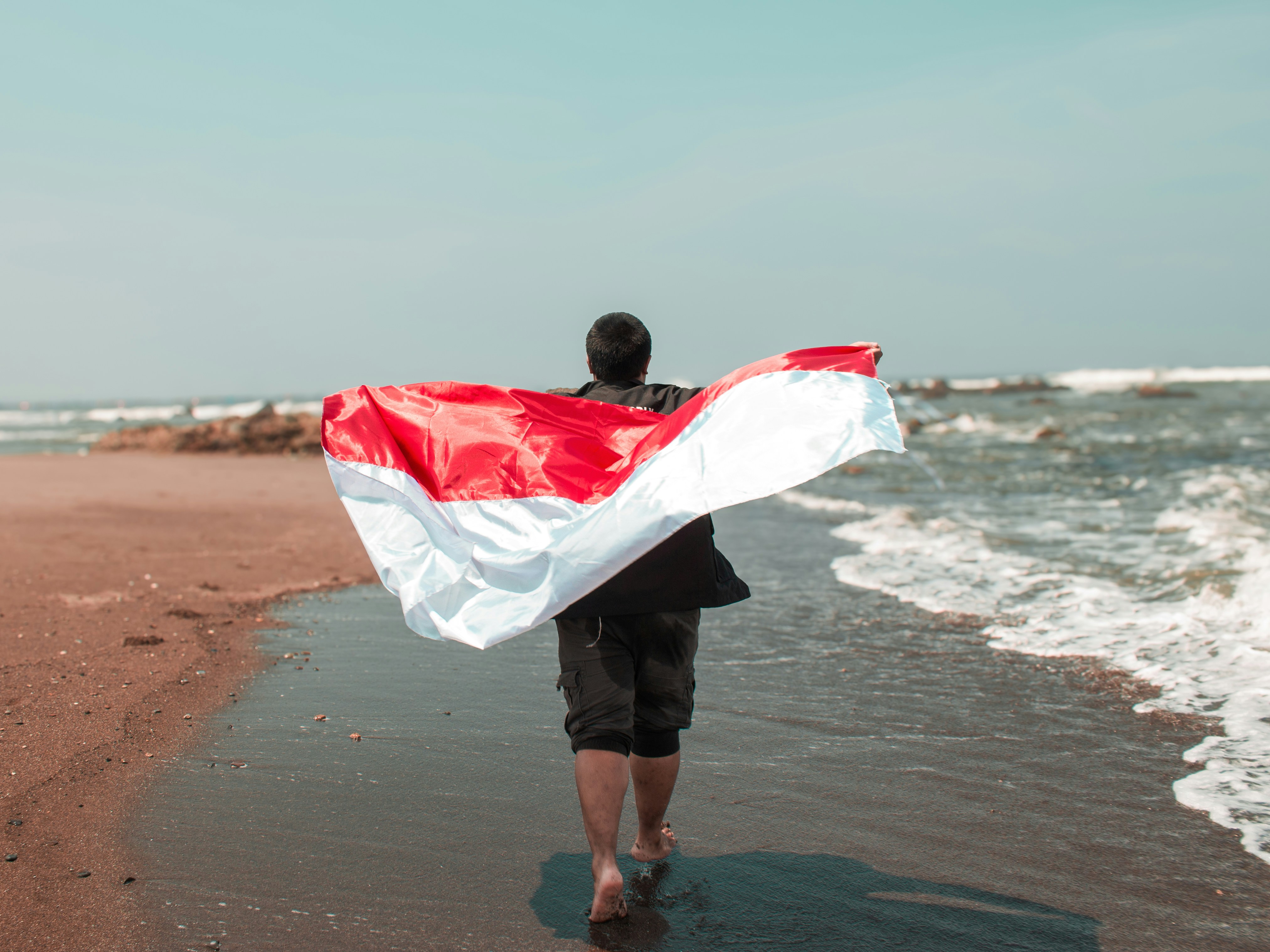 West Java, Indonesia. Image of people running bringing Indonesia flag to waving the flag at the beach for celebrate indenpedent day of Indonesia at 17 August, 2024.