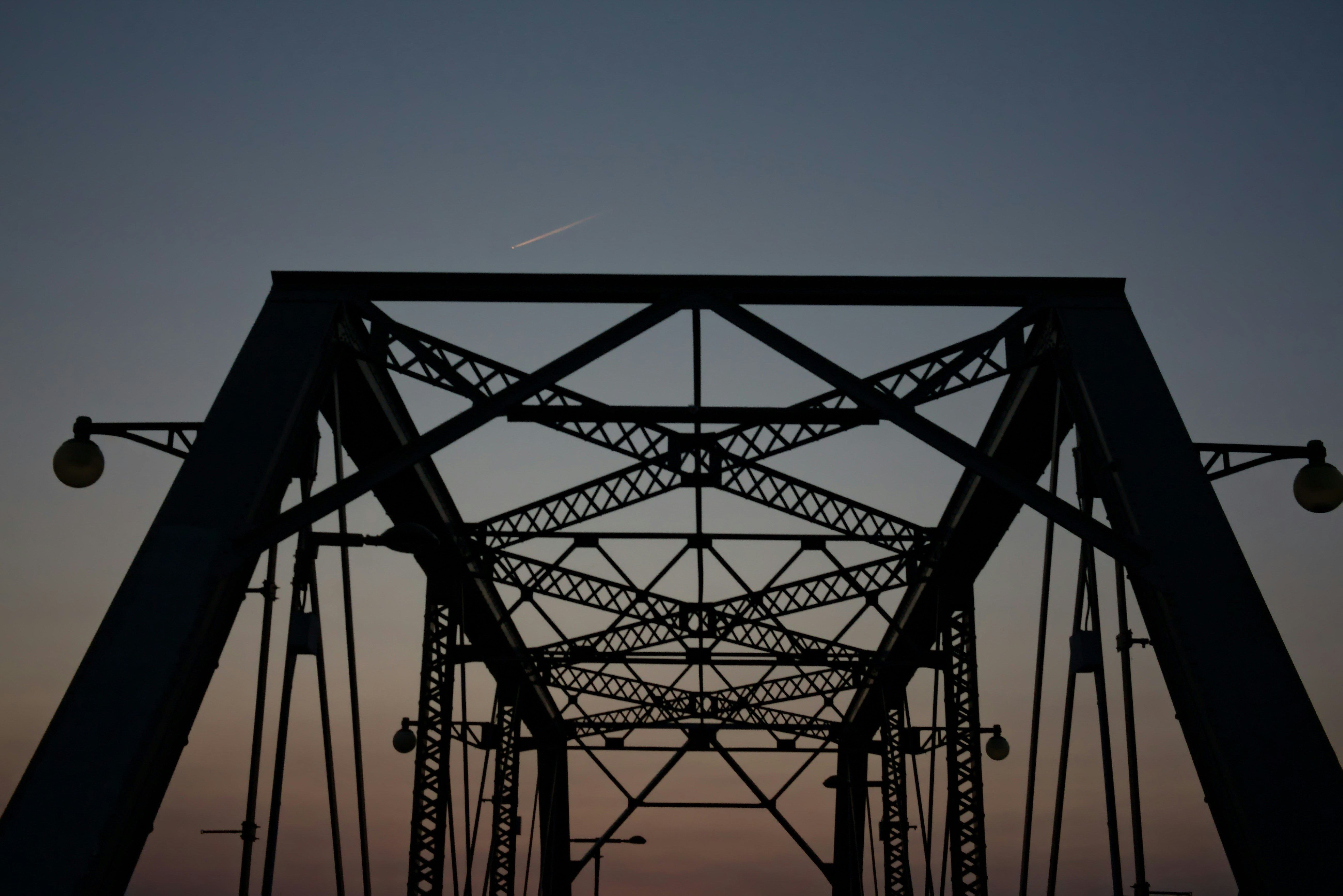 A view of a bridge with a plane flying over it photo – Free Wallpaper ...