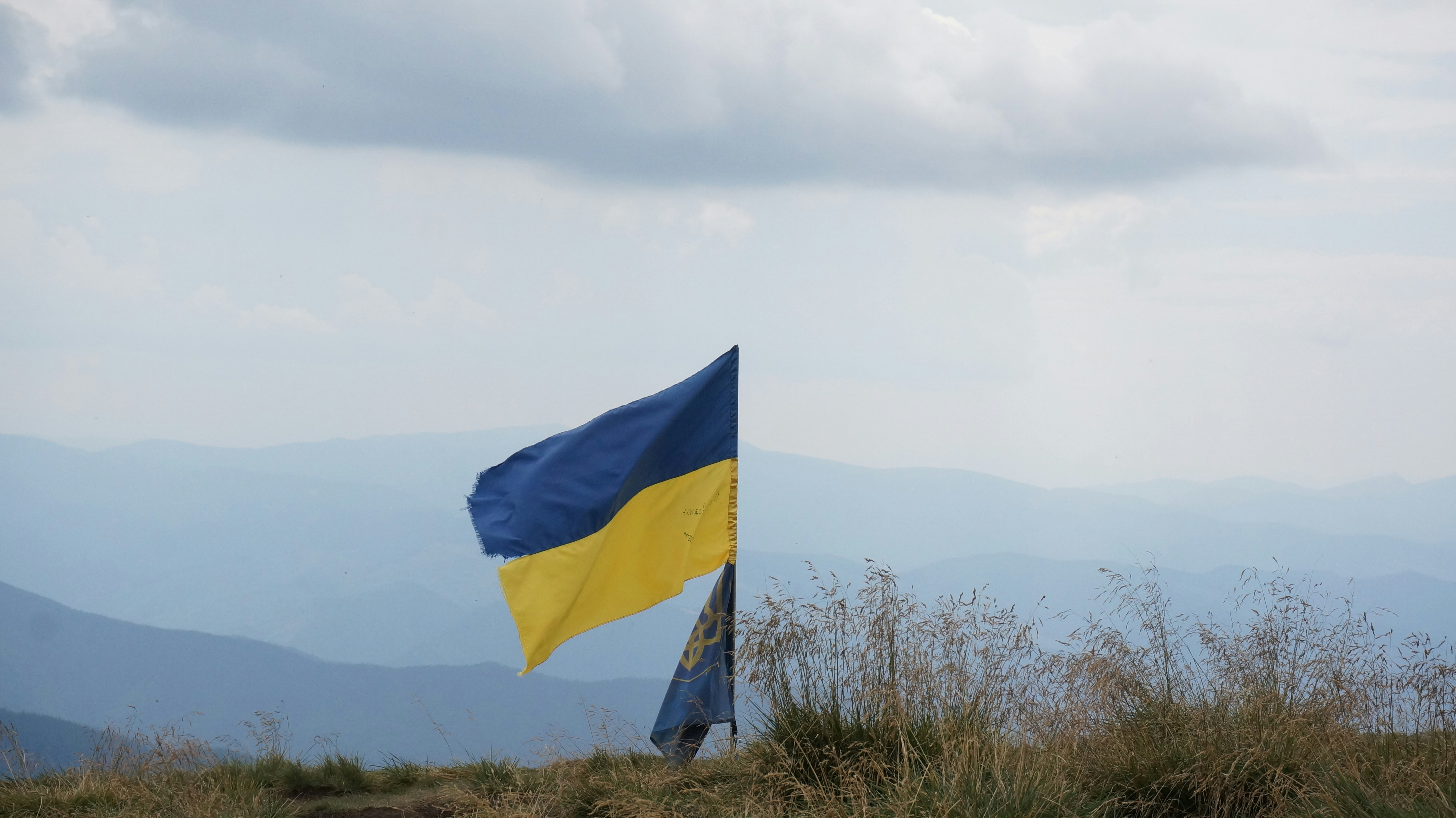 Flag on a Windswept Ridge: Blue-and-Yellow Banner Framing a Misty Horizon