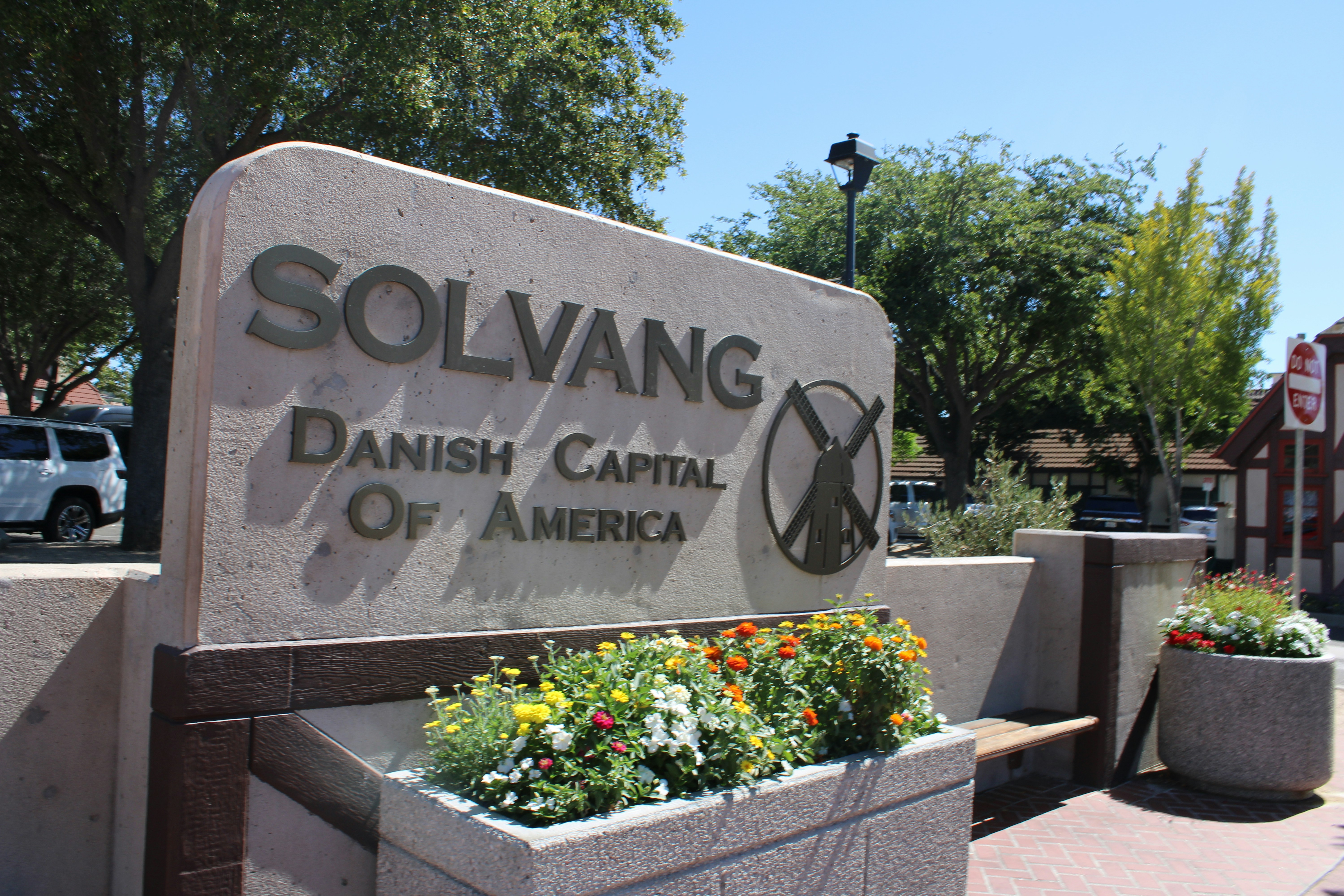 Signage marking Solvang as the 'Danish Capital of America,' adorned with vibrant flowers in planters.