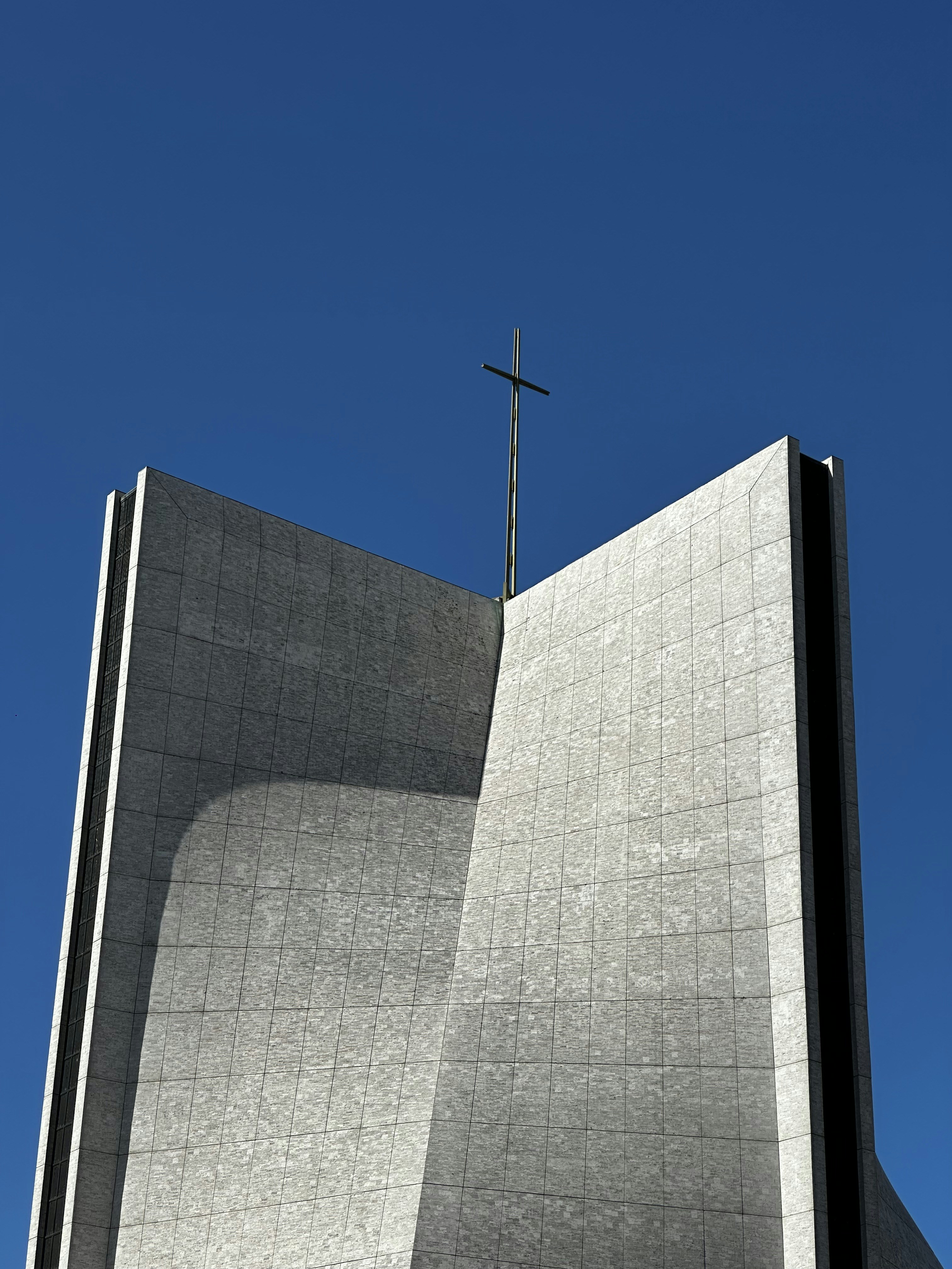 Cross Above the Facade: Concrete Geometry under a Pristine Blue Sky
