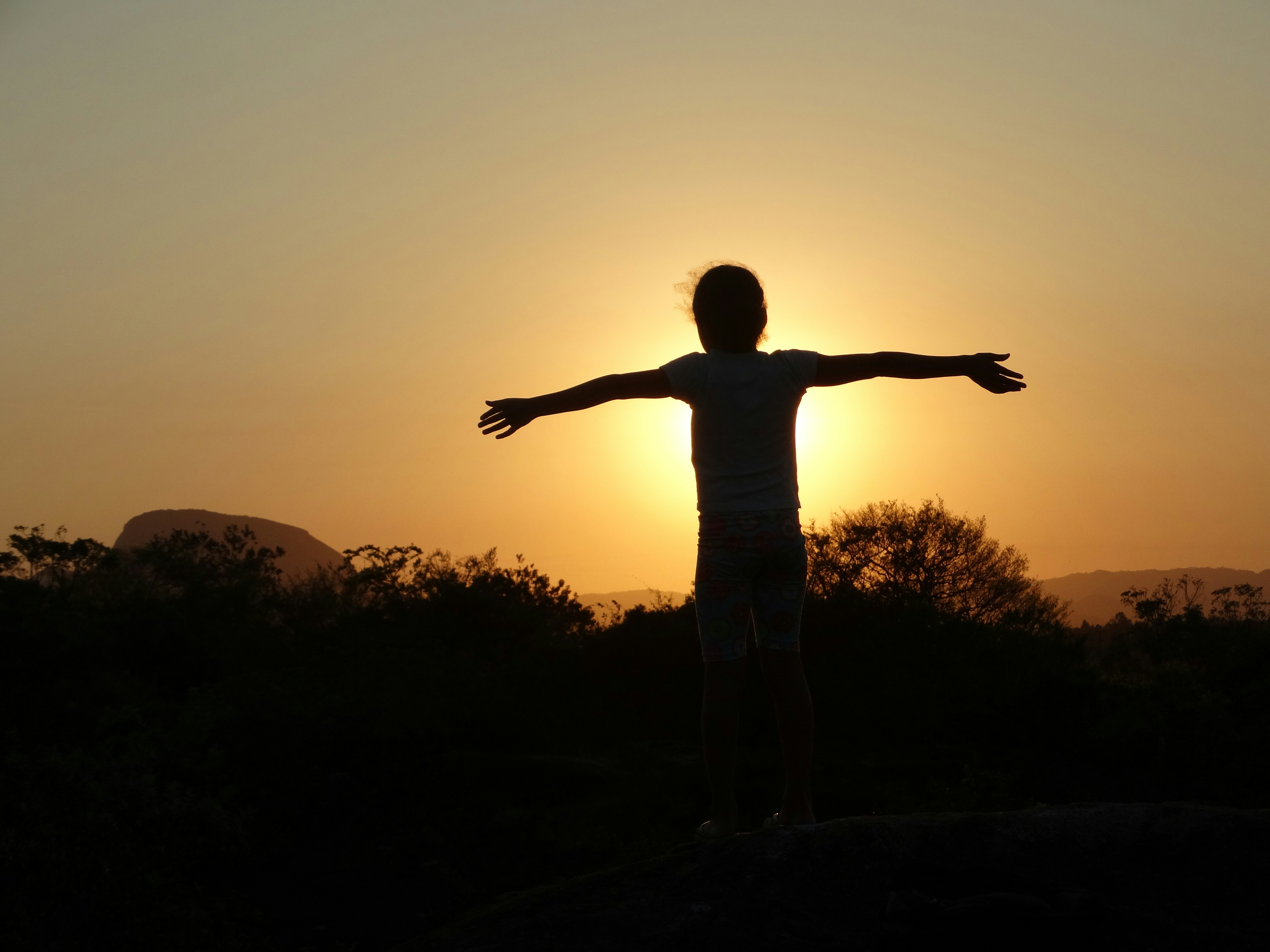Sunset Silhouette: A Child in Horizon with Outstretched Arms