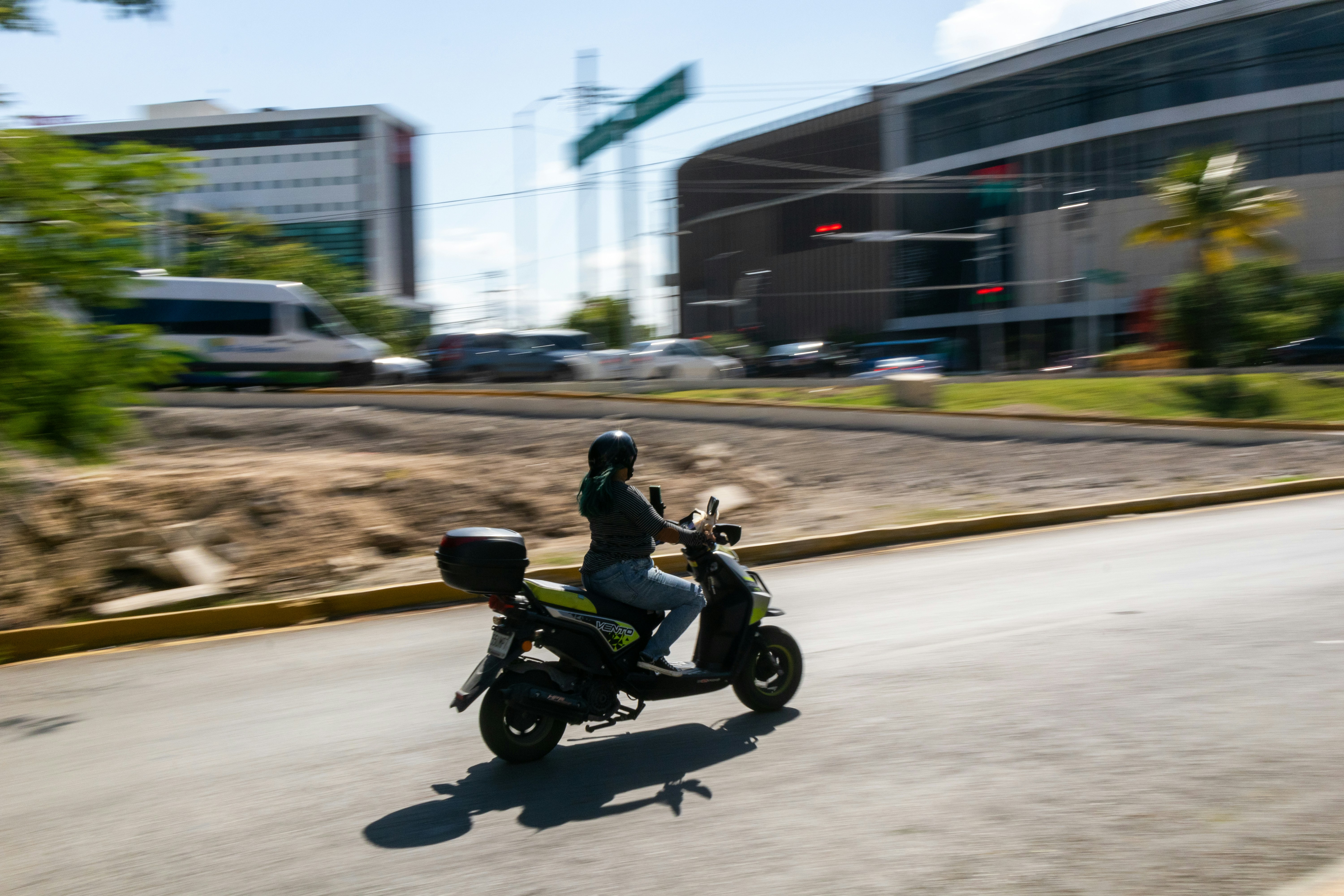 Motorcyclist rides swiftly through a city street, with motion blur capturing the sense of speed.