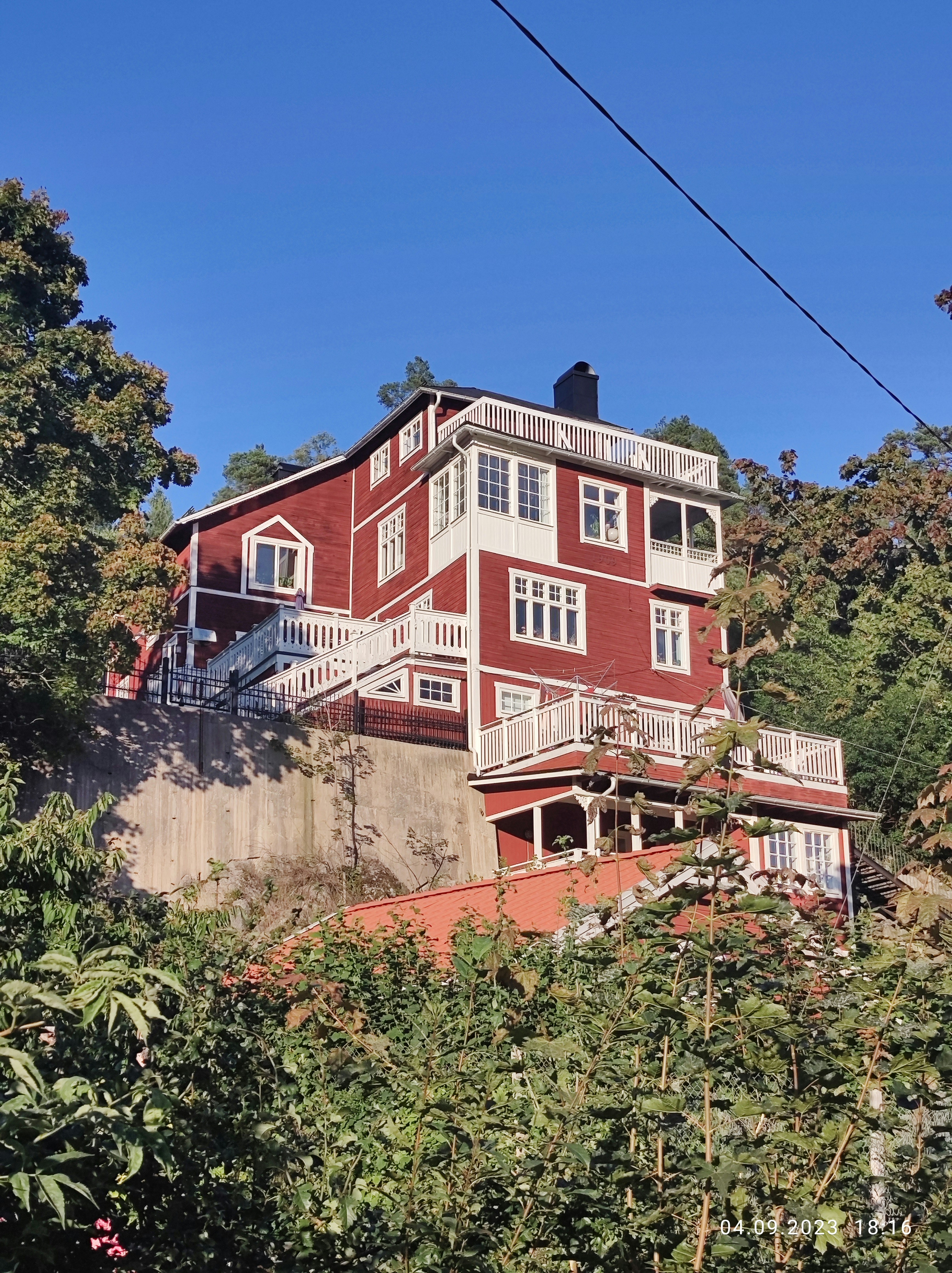 A red house sitting on top of a lush green hillside