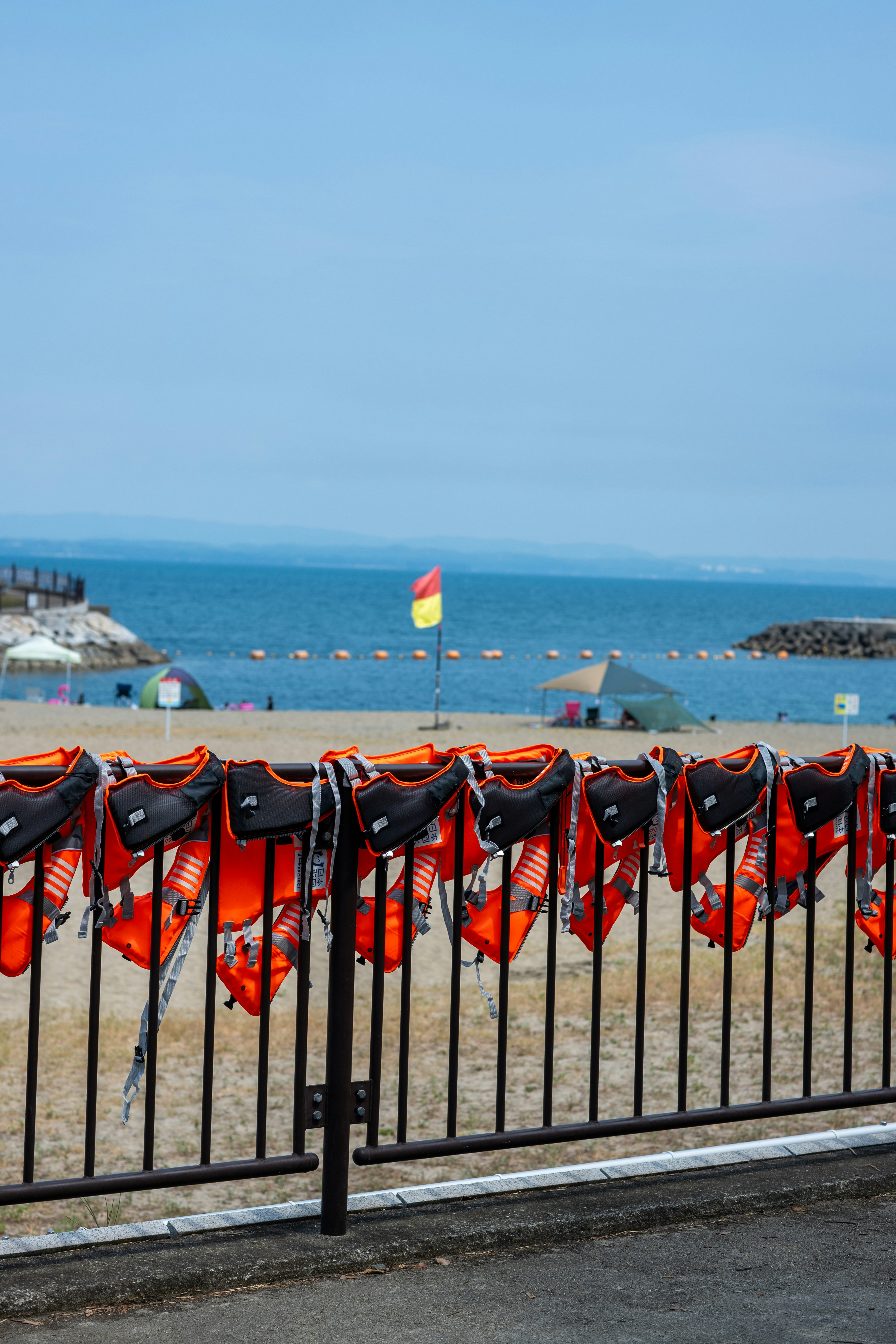 Orange Lifebelts Line a Beach Fence, Framing a Quiet Seascape