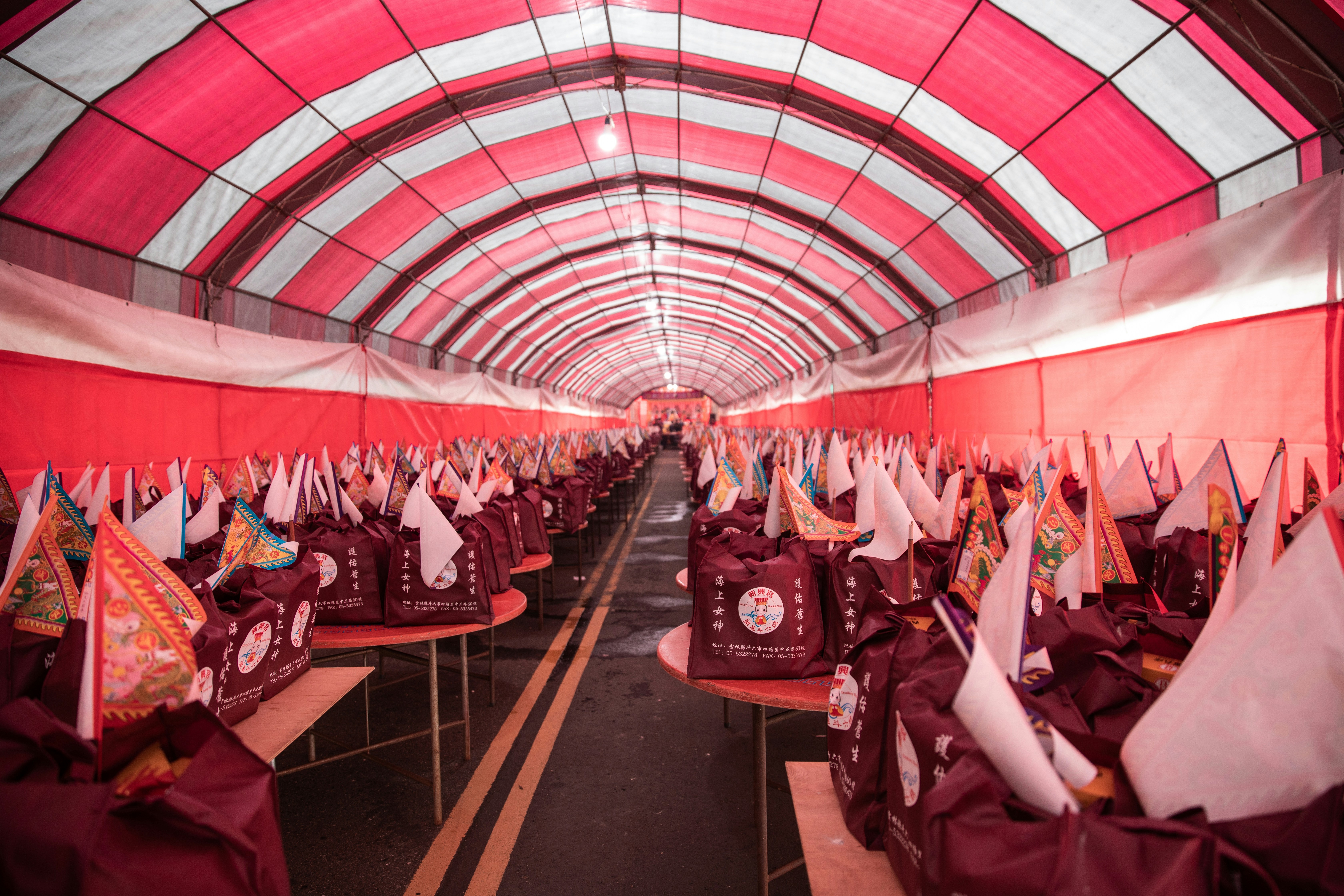 Symmetrical Banquet Hall Aisle: Rows of Maroon Seats Under a Red-White Canopy