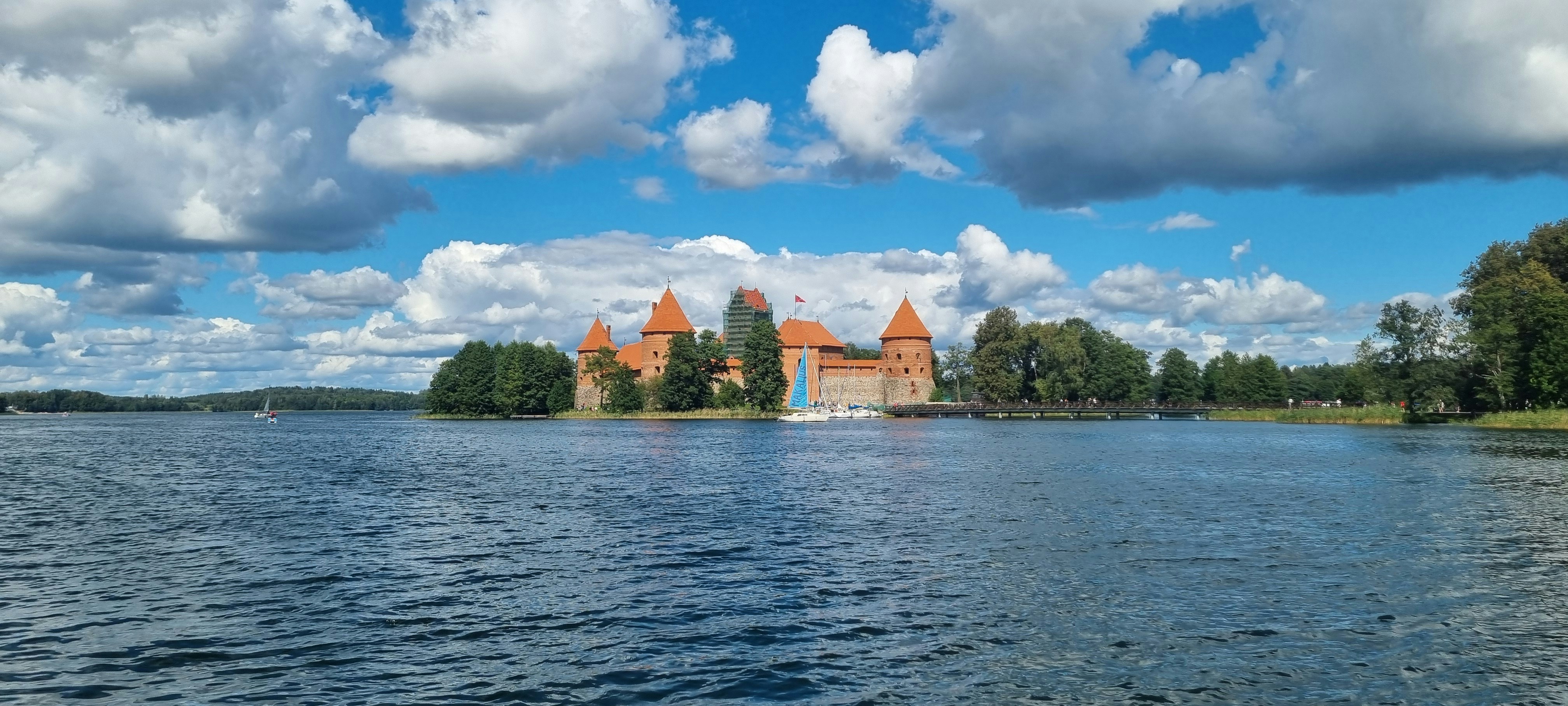 A large body of water surrounded by trees and clouds photo – Free ...